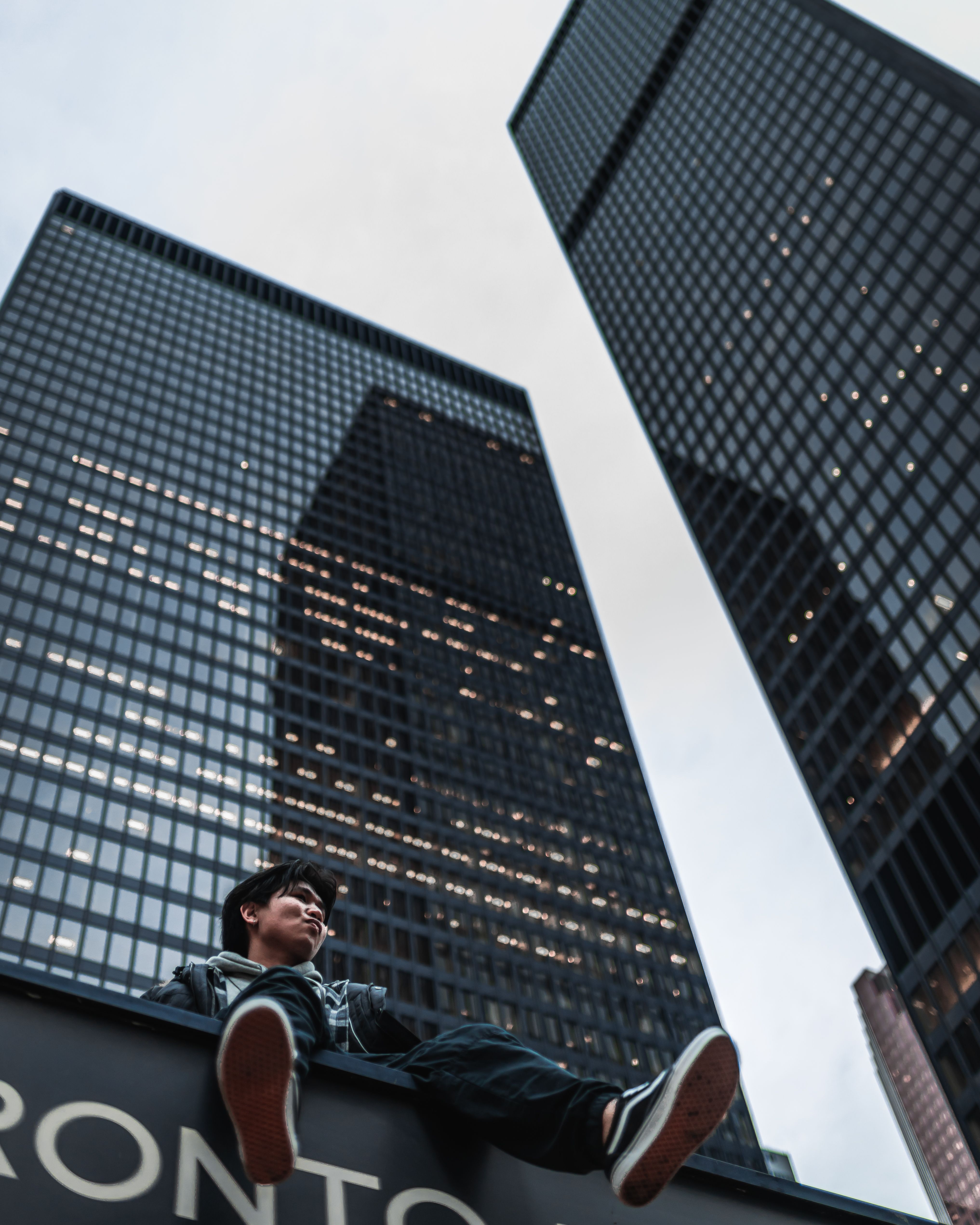 Man Sitting in Front of High Rise Building · Free Stock Photo