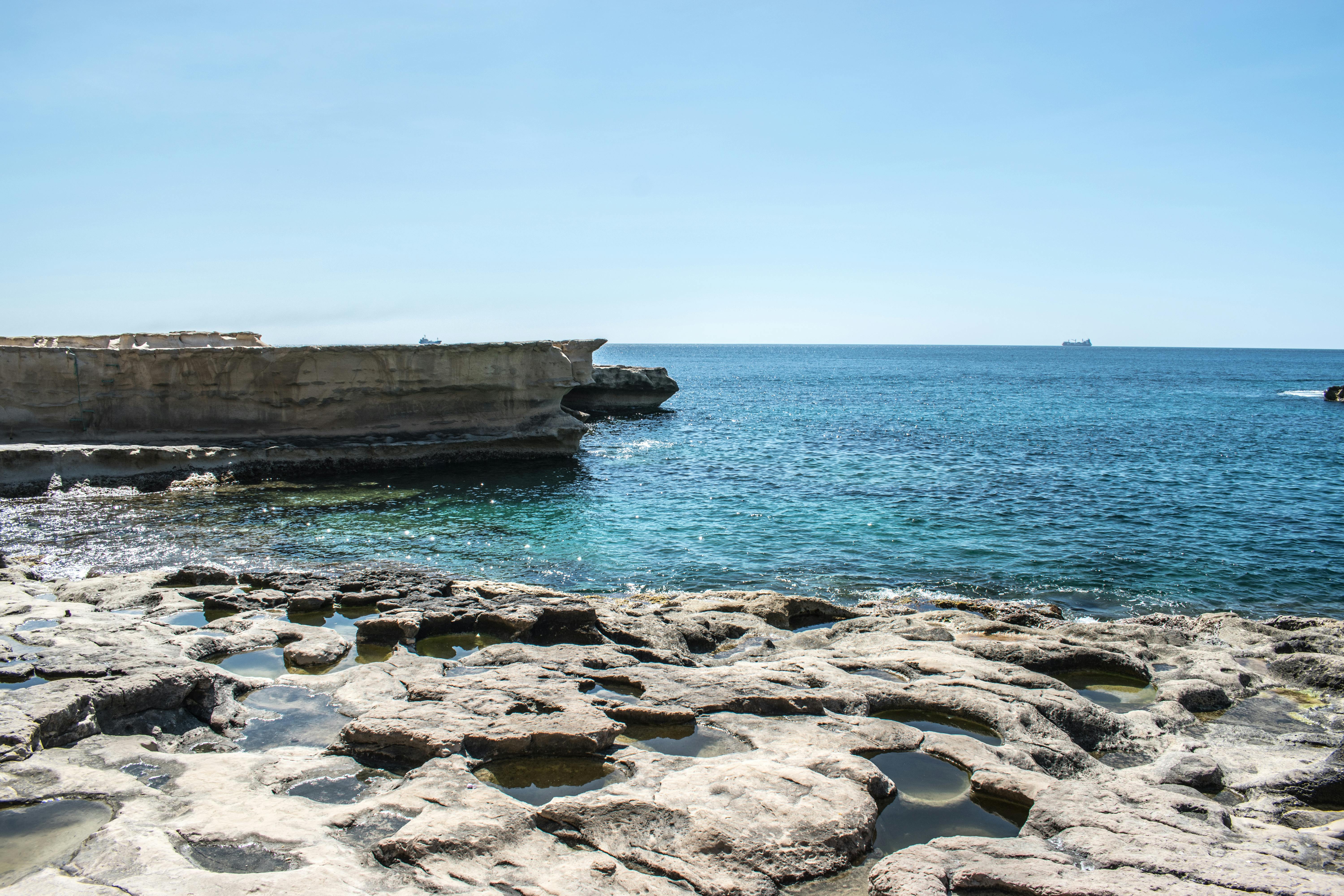 Brown Rock Formation on Sea Under Blue Sky · Free Stock Photo
