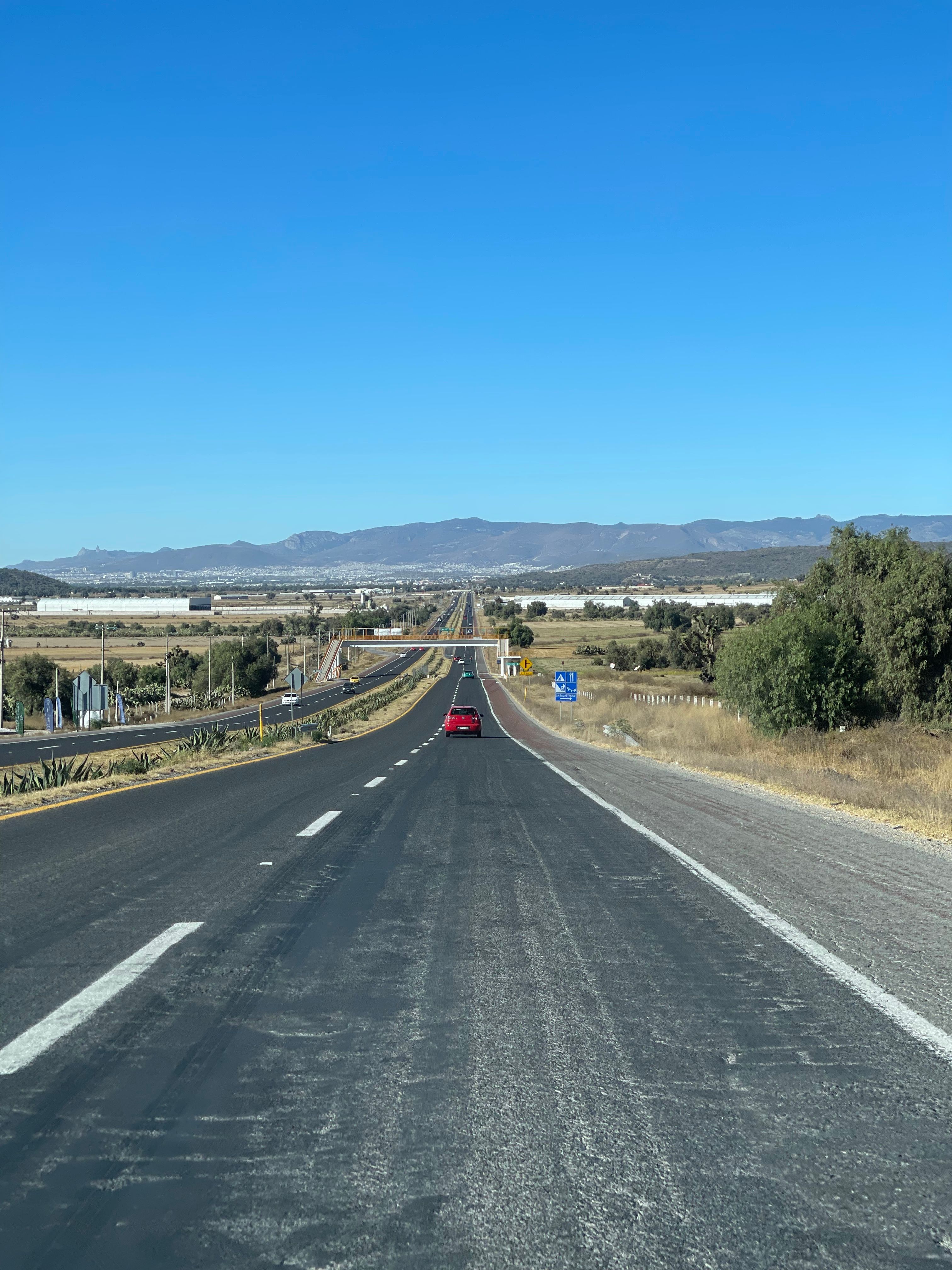 A Long Road Between Brown Field Under Blue Sky · Free Stock Photo