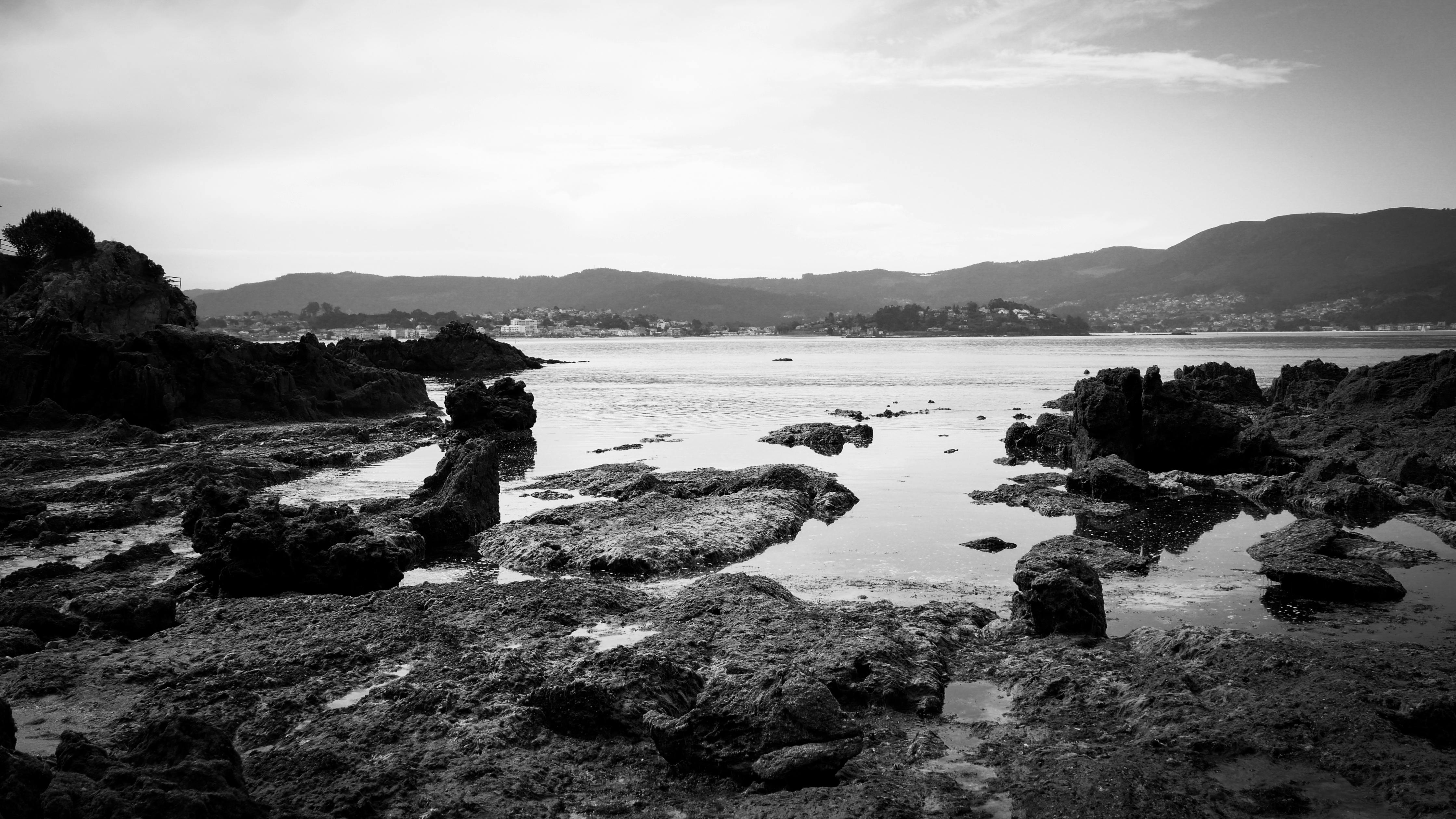 Grayscale Photo of Rocks on Seashore · Free Stock Photo