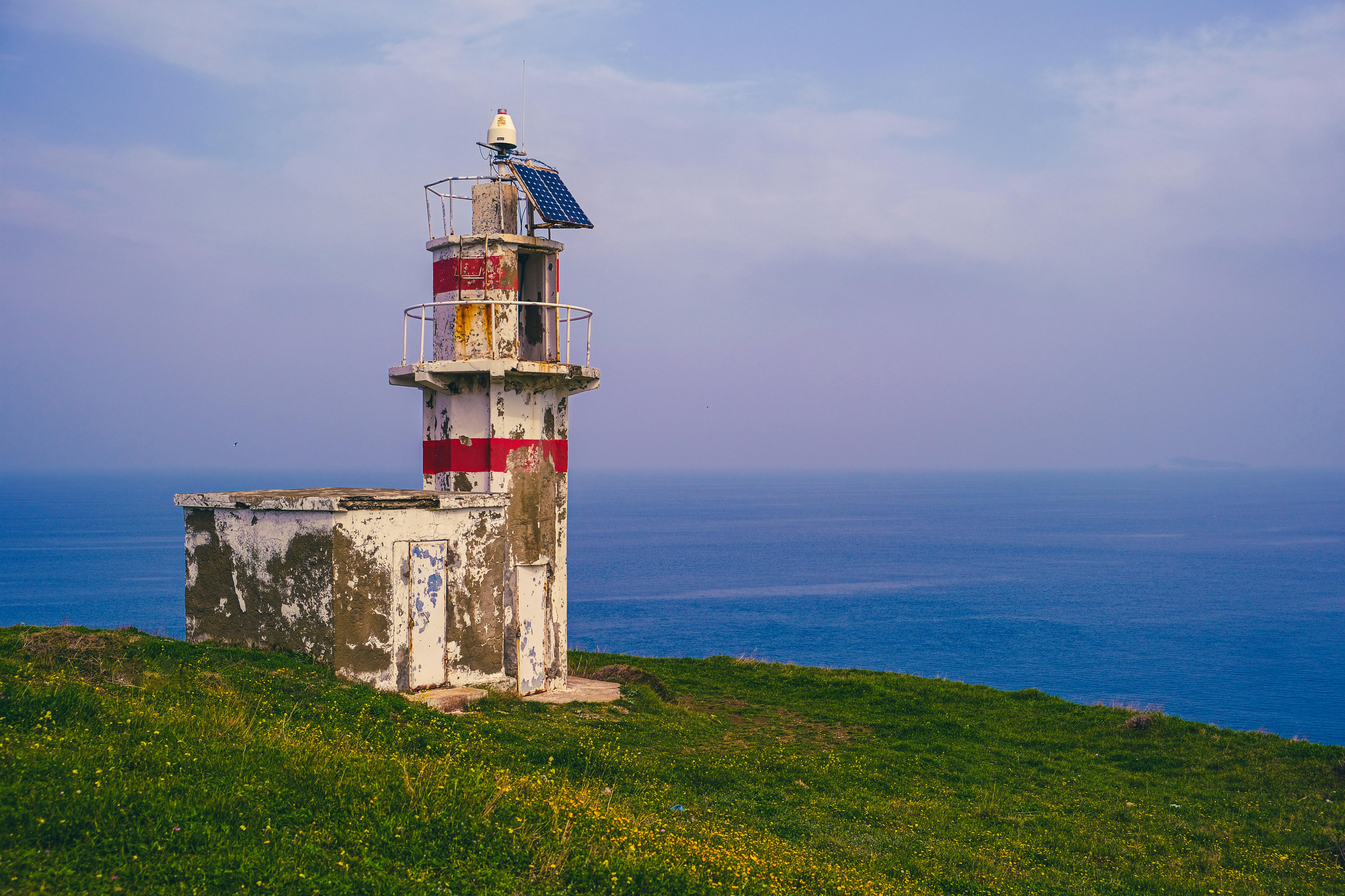 Weathered Lighthouse Overlooking Blue Sea · Free Stock Photo