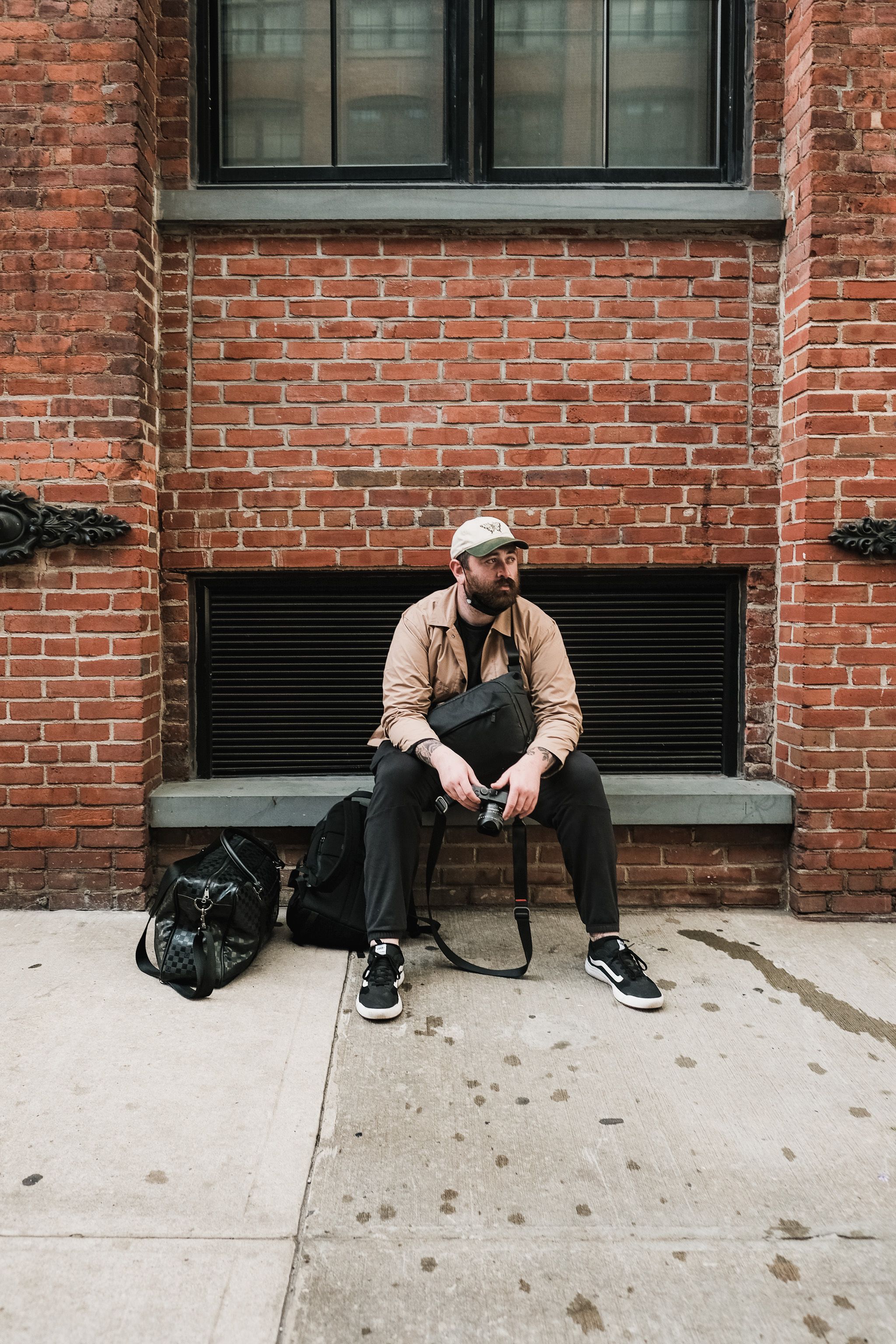 Man Sitting on Concrete Bench Beside the Brick Wall · Free Stock Photo