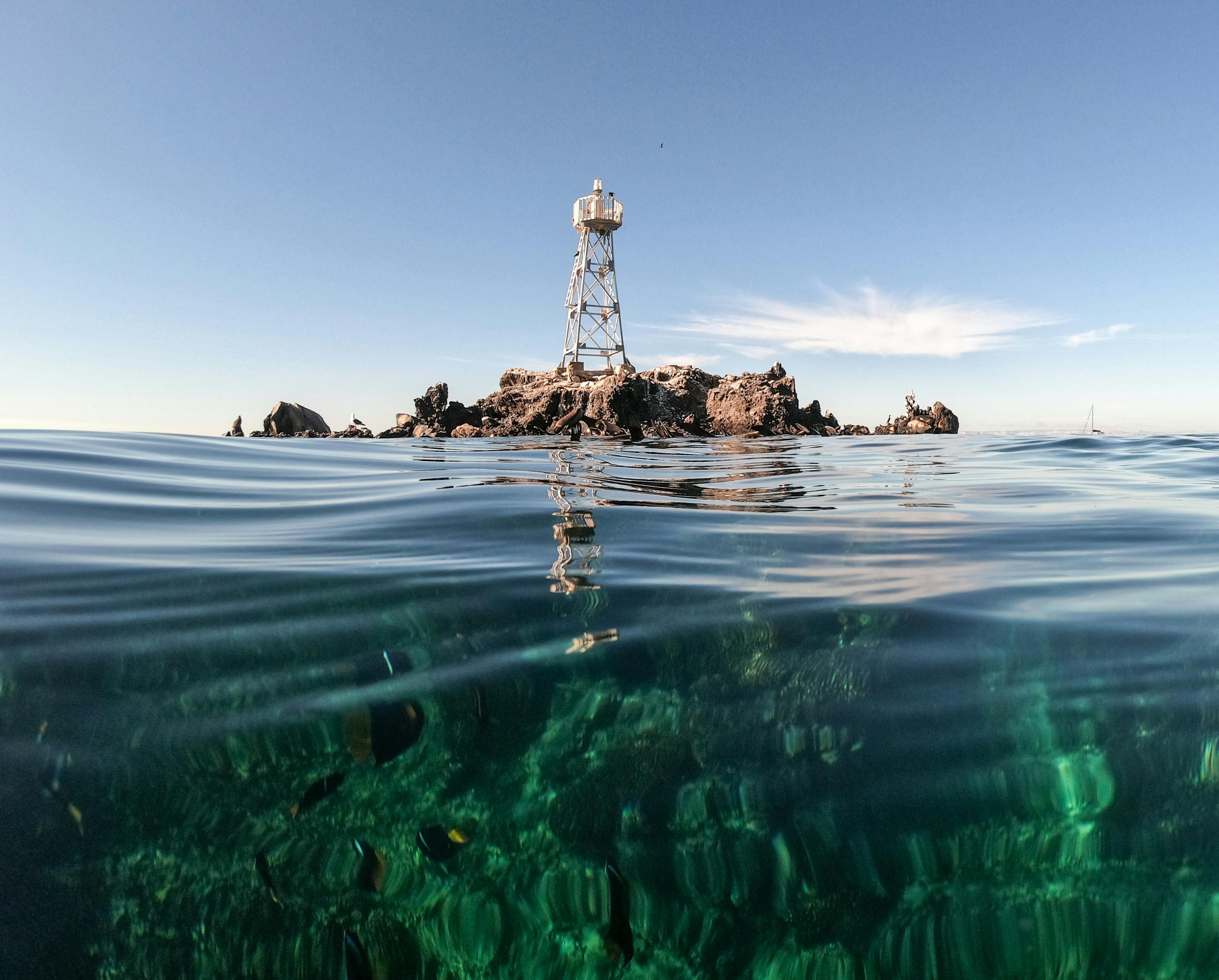 Red Lighthouse on Top of Hills Beside Sea · Free Stock Photo