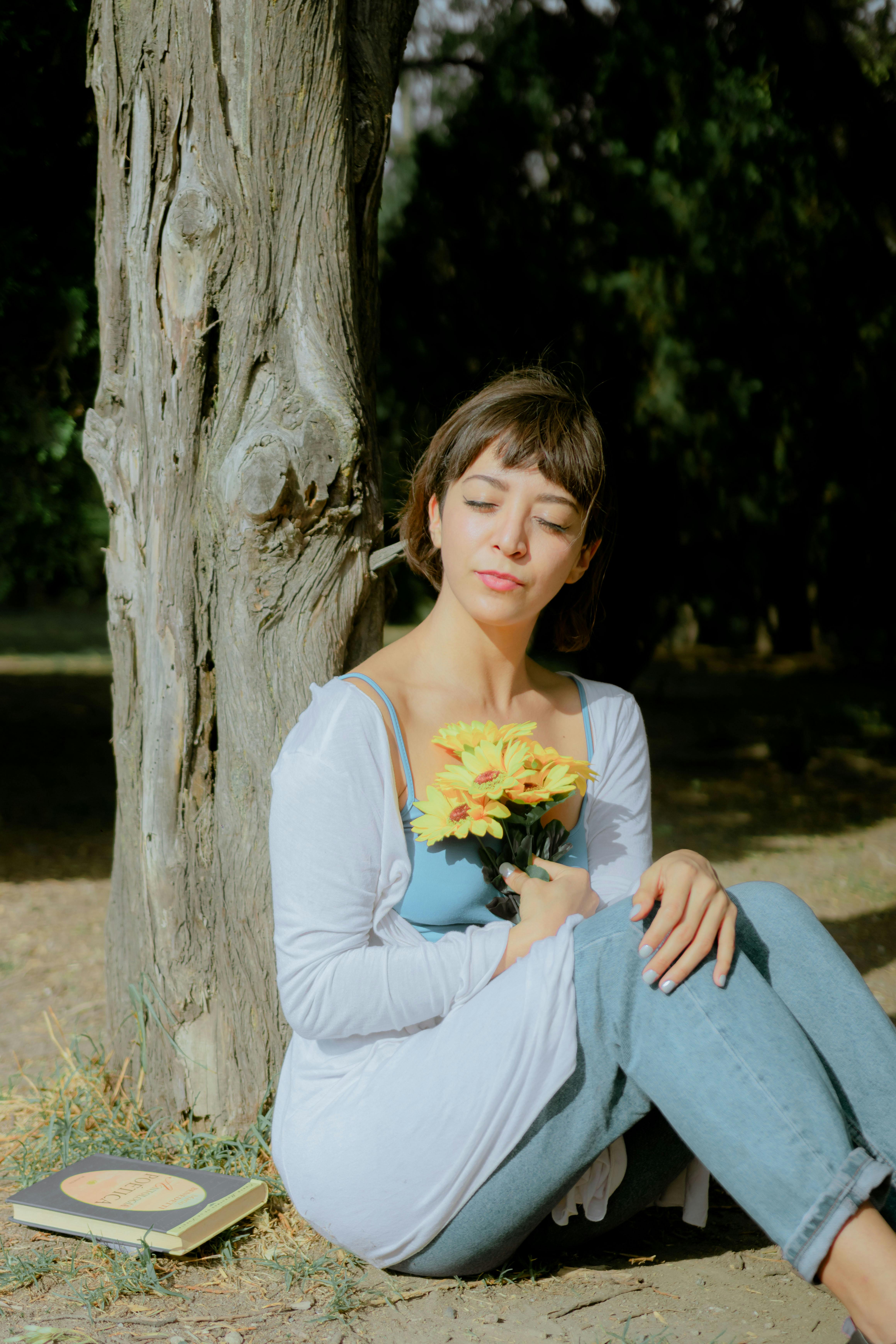 Woman with Flowers Sitting next to Tree · Free Stock Photo