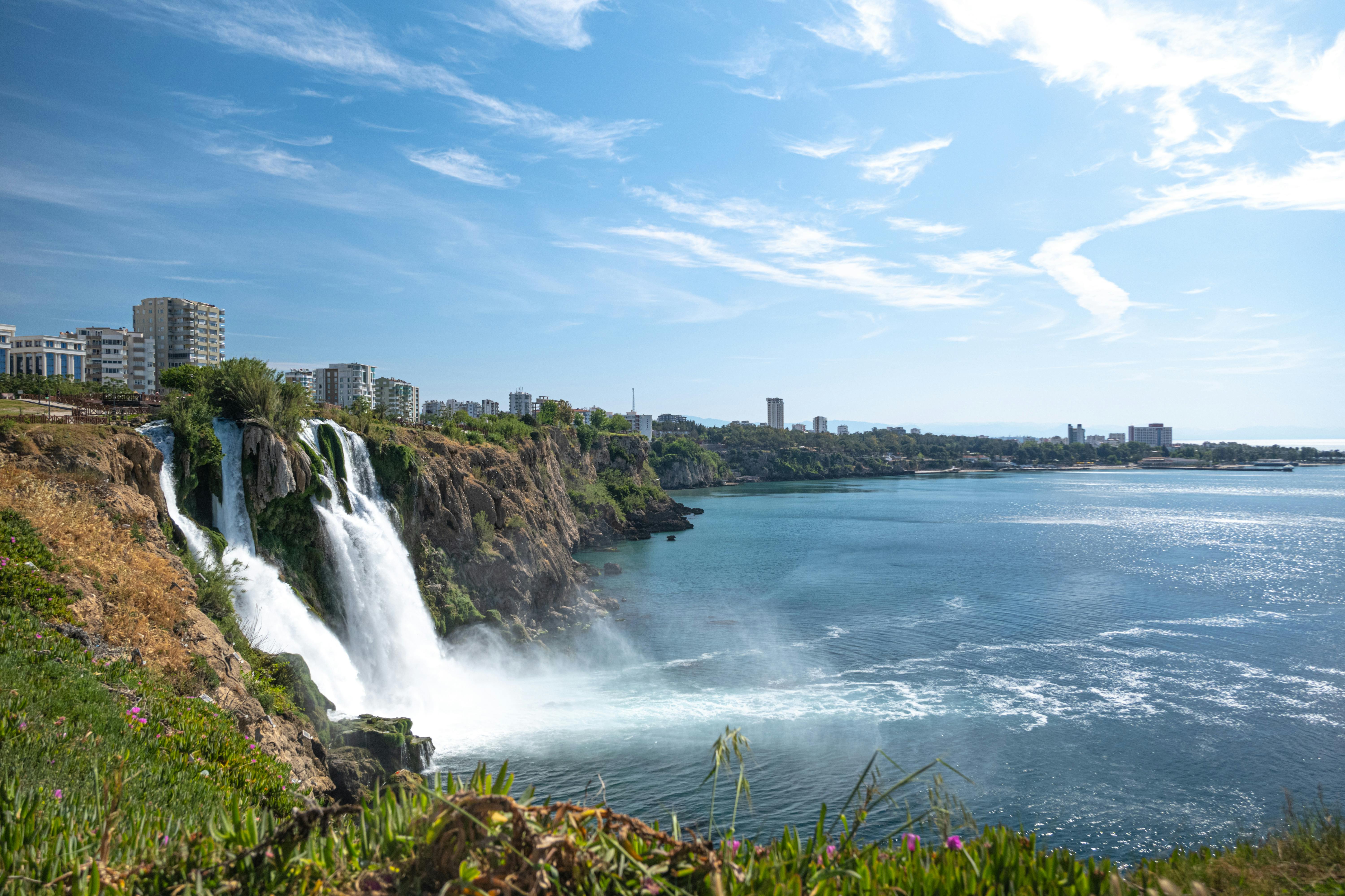 Green Grass Near Water Falls under Blue Sky · Free Stock Photo