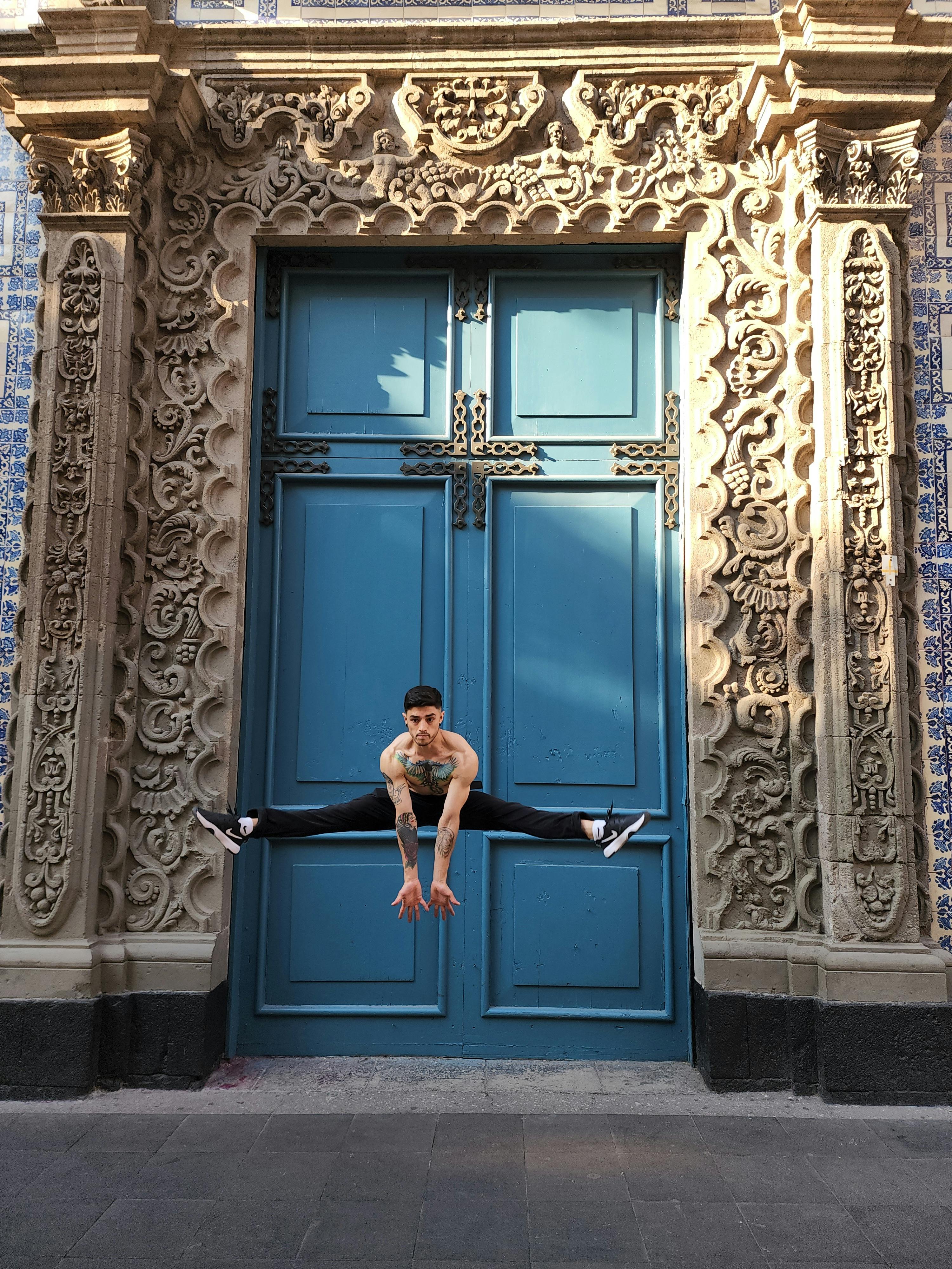A Man Doing a Jump Split in front of Double Doors · Free Stock Photo