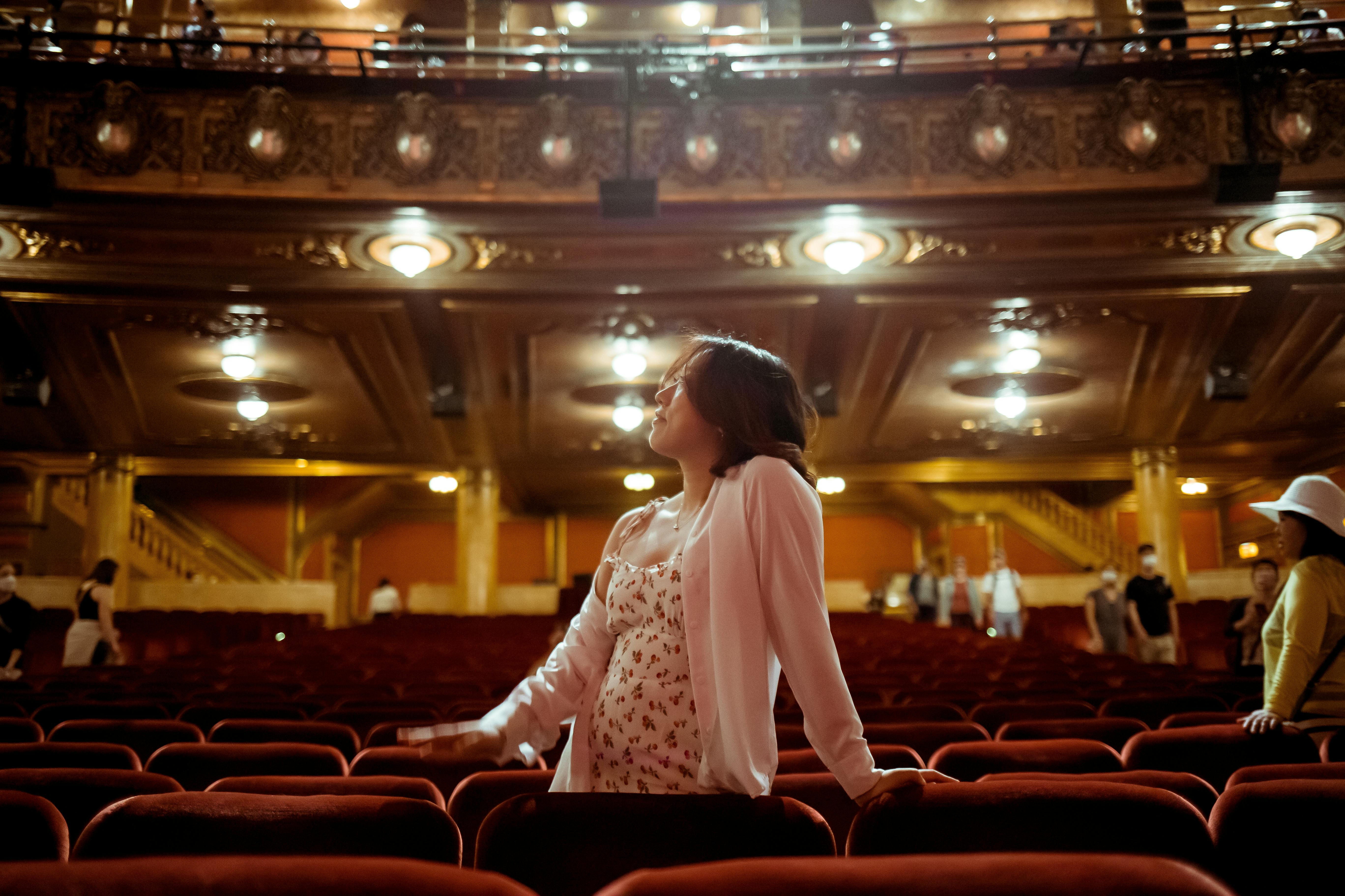 Woman in Dress Posing in Theatre near Chairs · Free Stock Photo