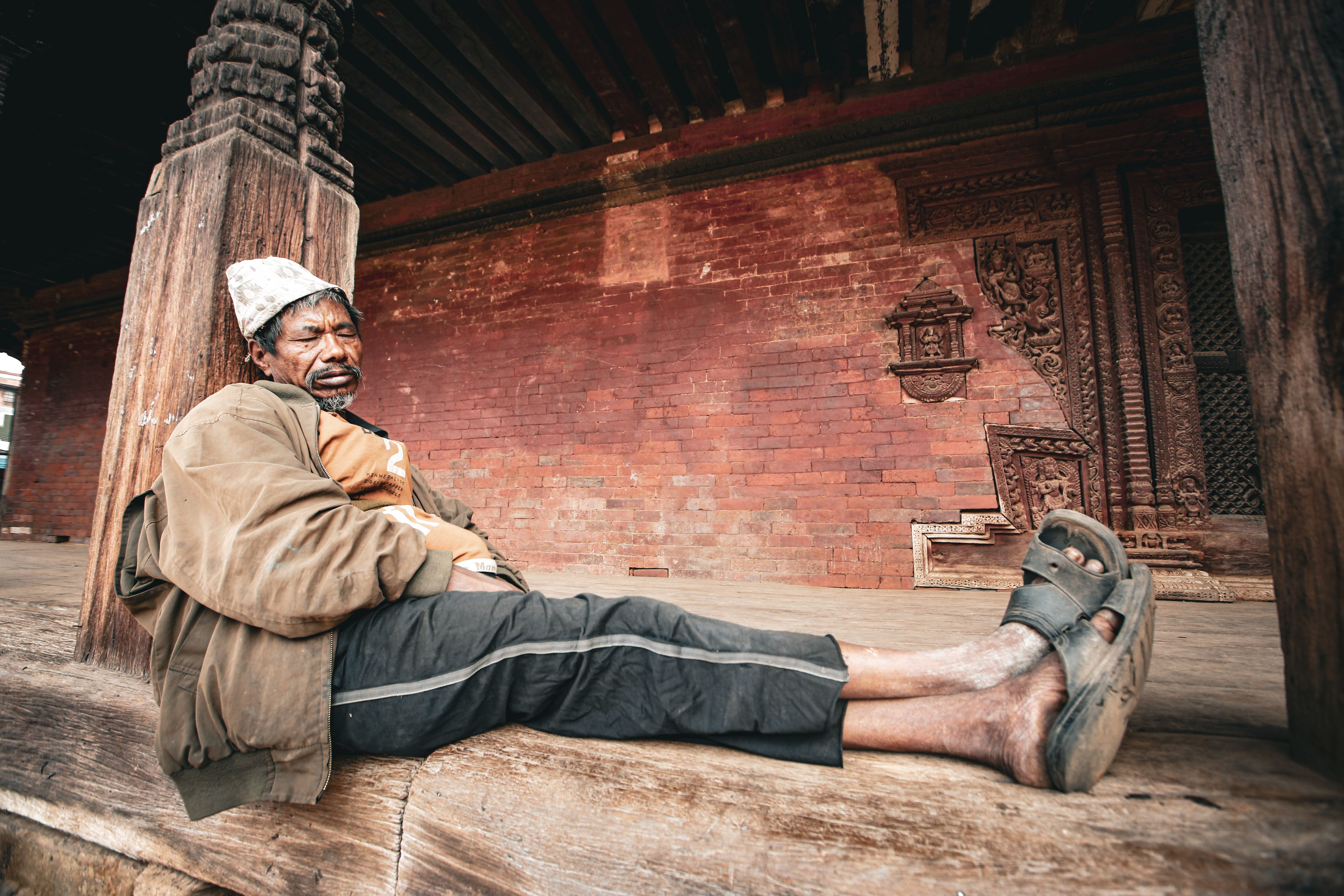 Man Sleeping Beside a Wooden Post · Free Stock Photo