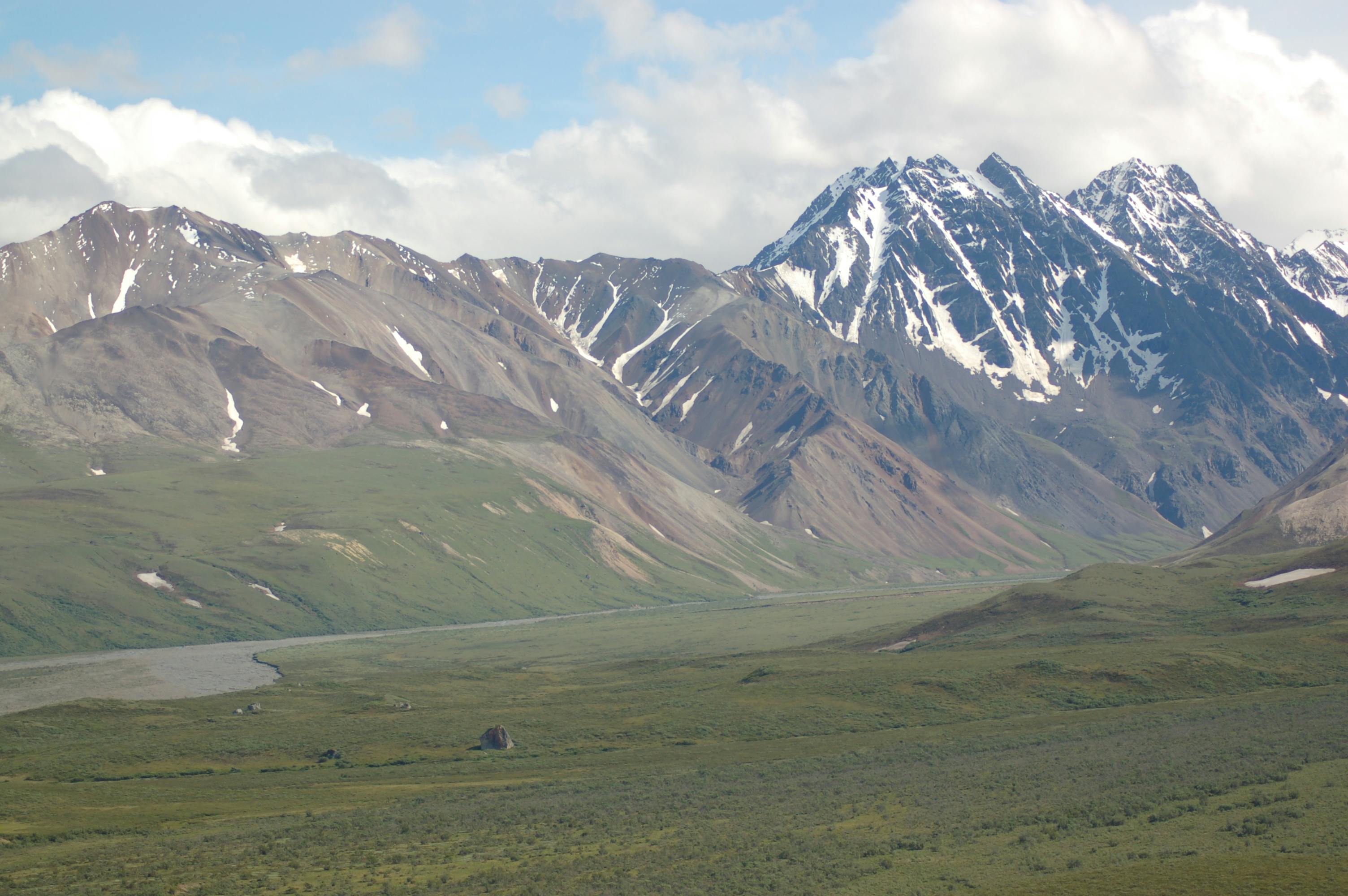 A Green Grass Field Between Mountains · Free Stock Photo