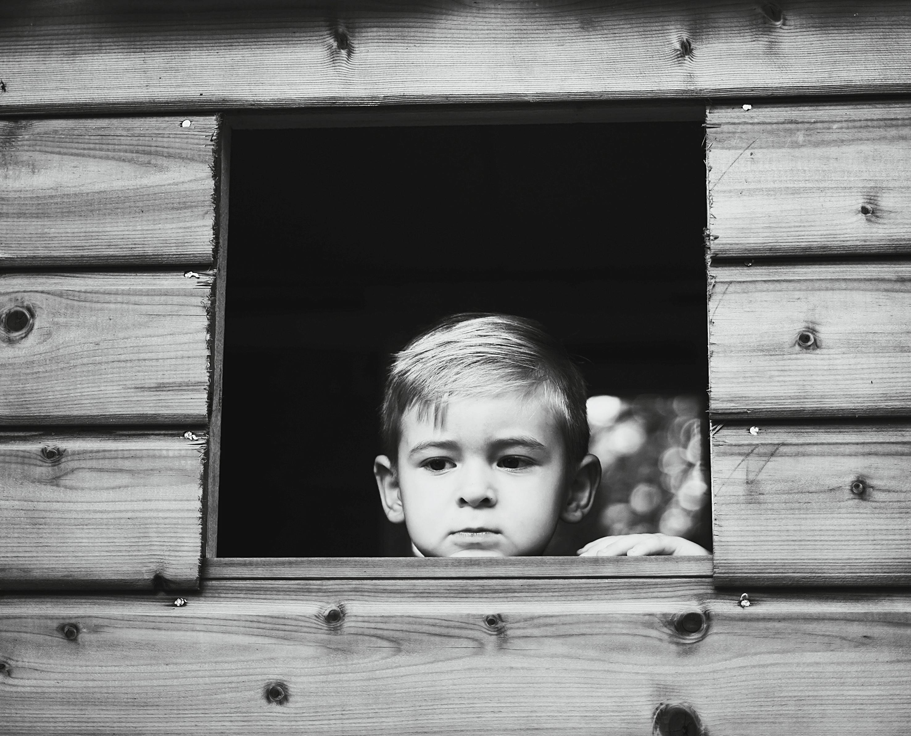 Grayscale Photo of a Boy on a Wooden Window · Free Stock Photo