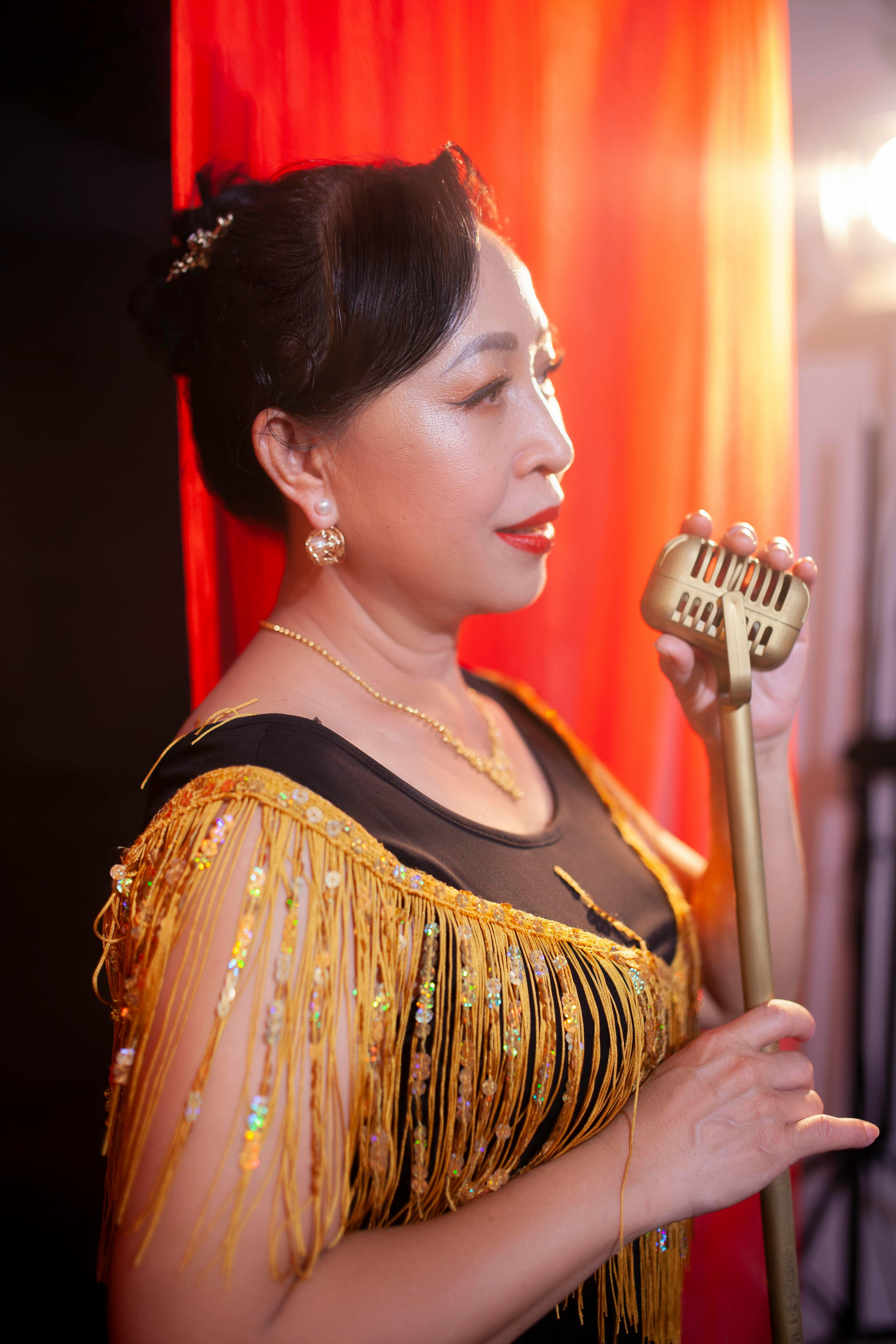 A Woman in Gold and Black Top Holding a Microphone · Free Stock Photo
