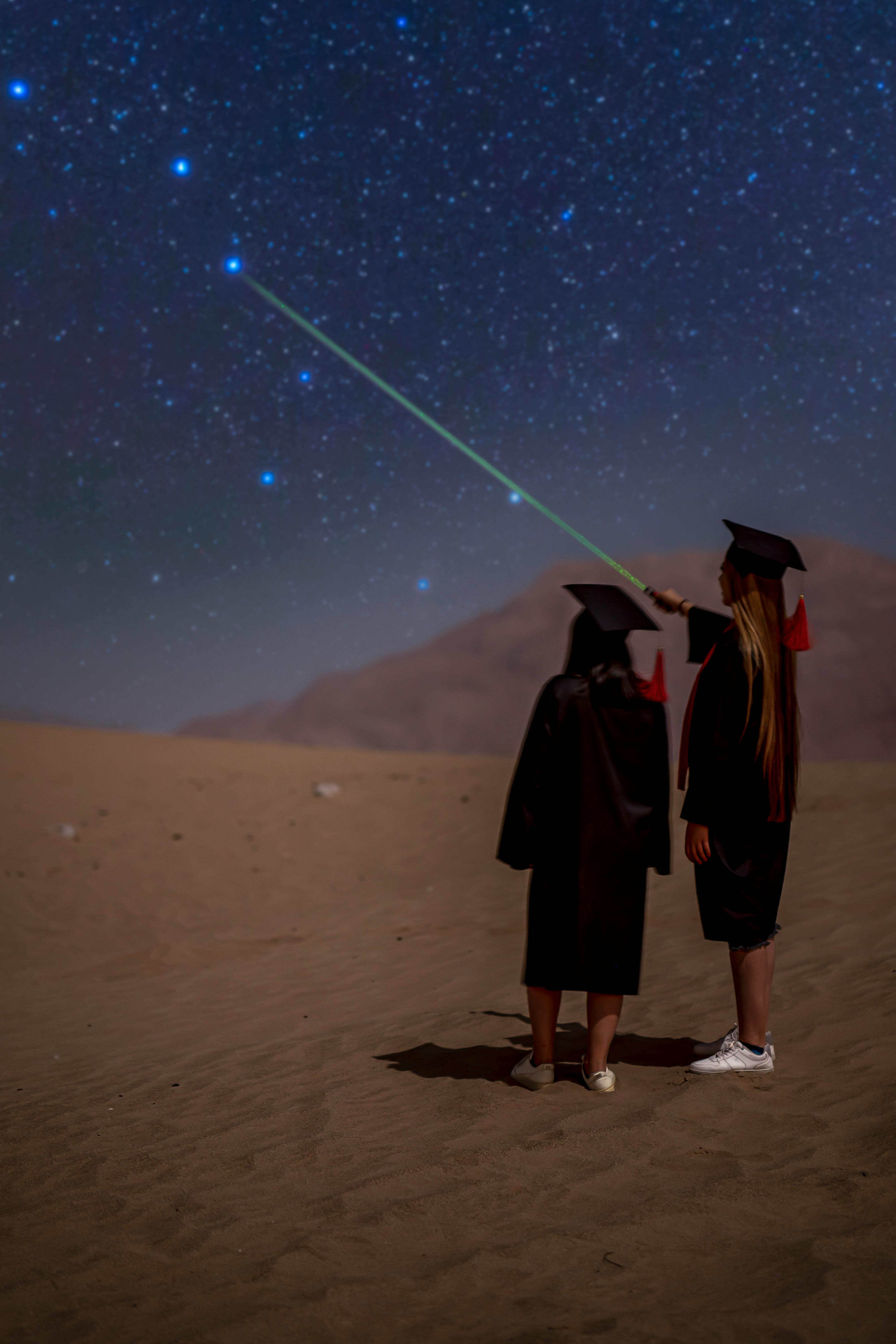 Young Graduates Pointing a Flashlight in the Sky · Free Stock Photo