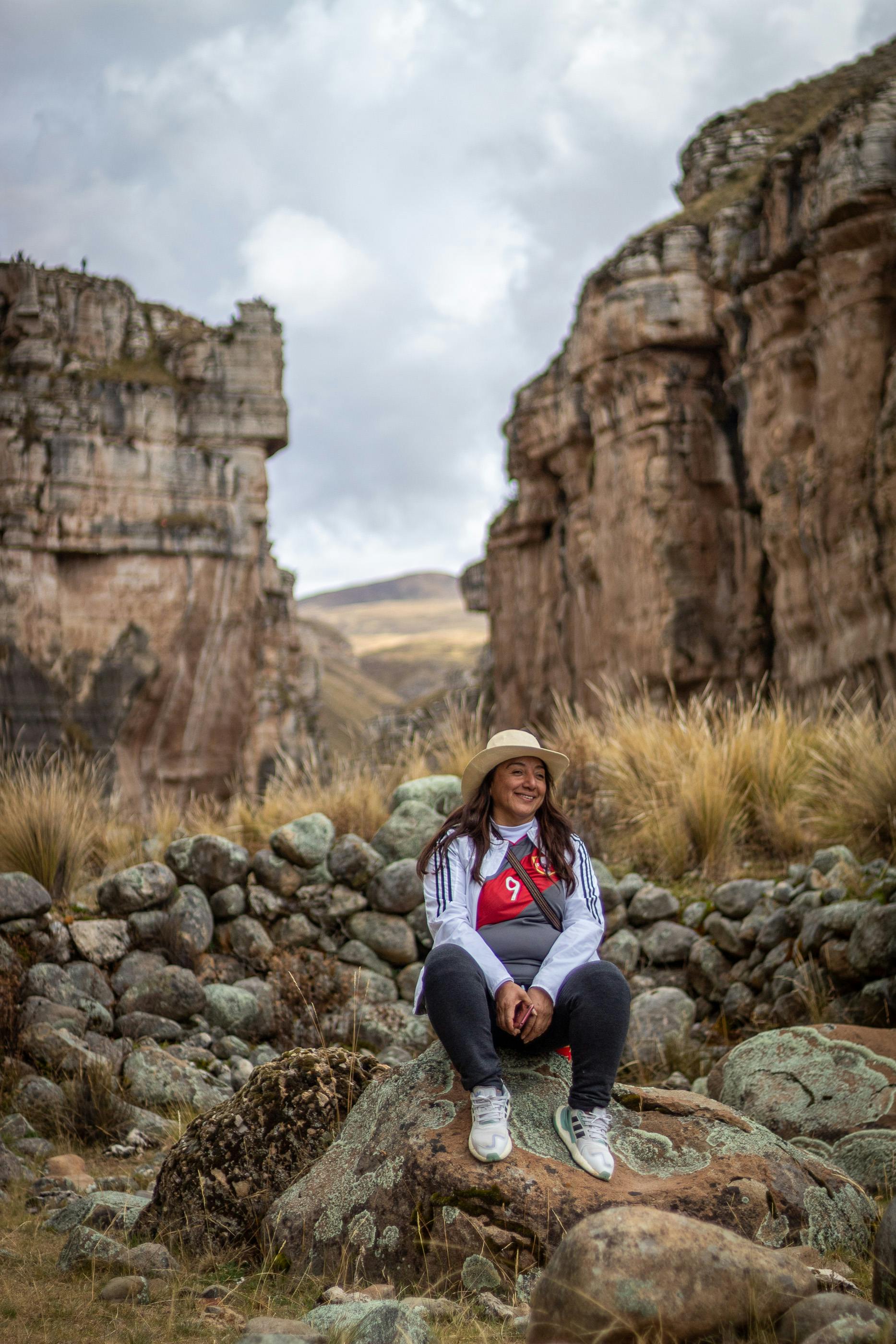Smiling Woman Sitting on Stones near Rock Formations · Free Stock Photo