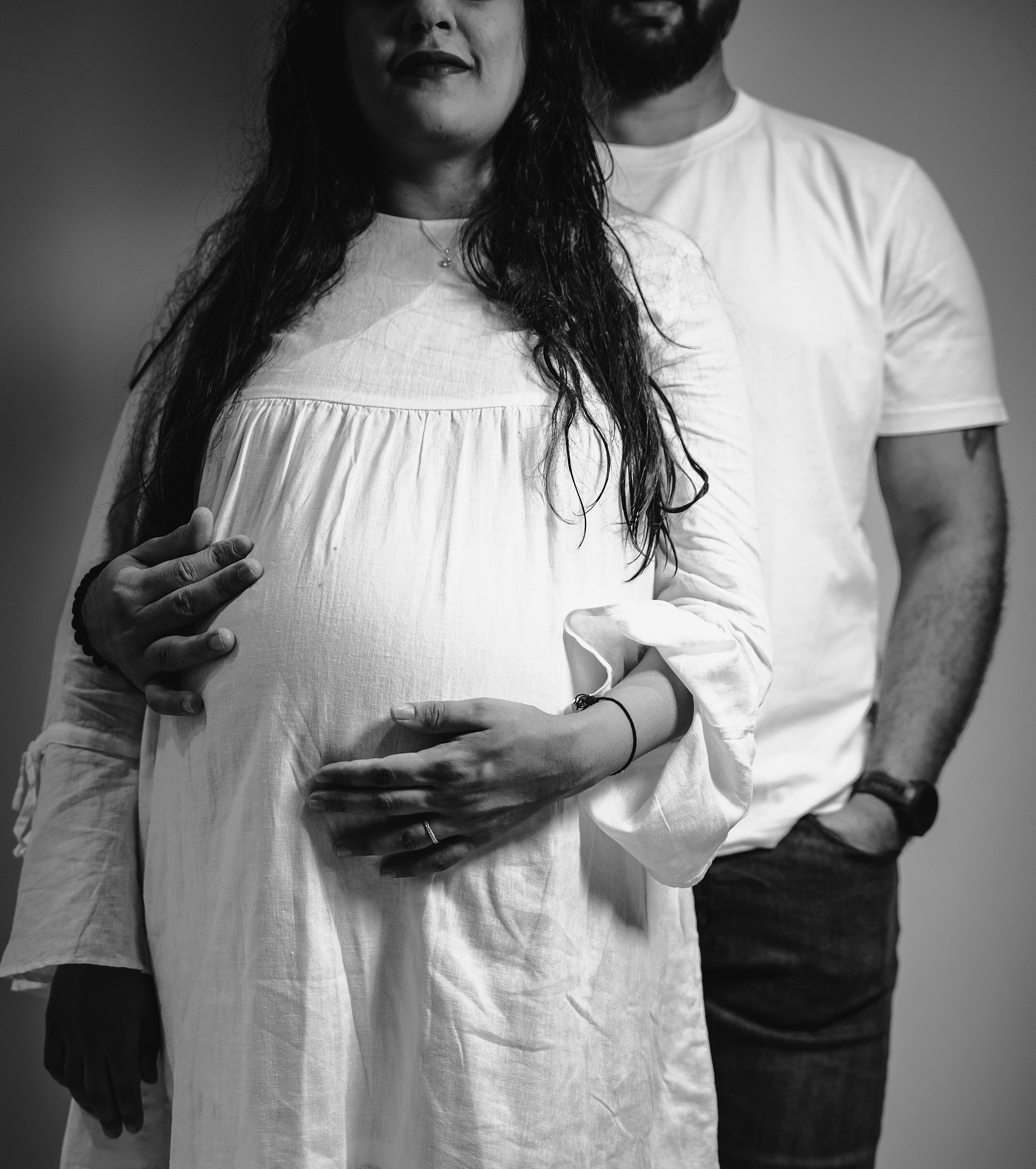 A Grayscale of a Couple Holding a Baby Bump · Free Stock Photo