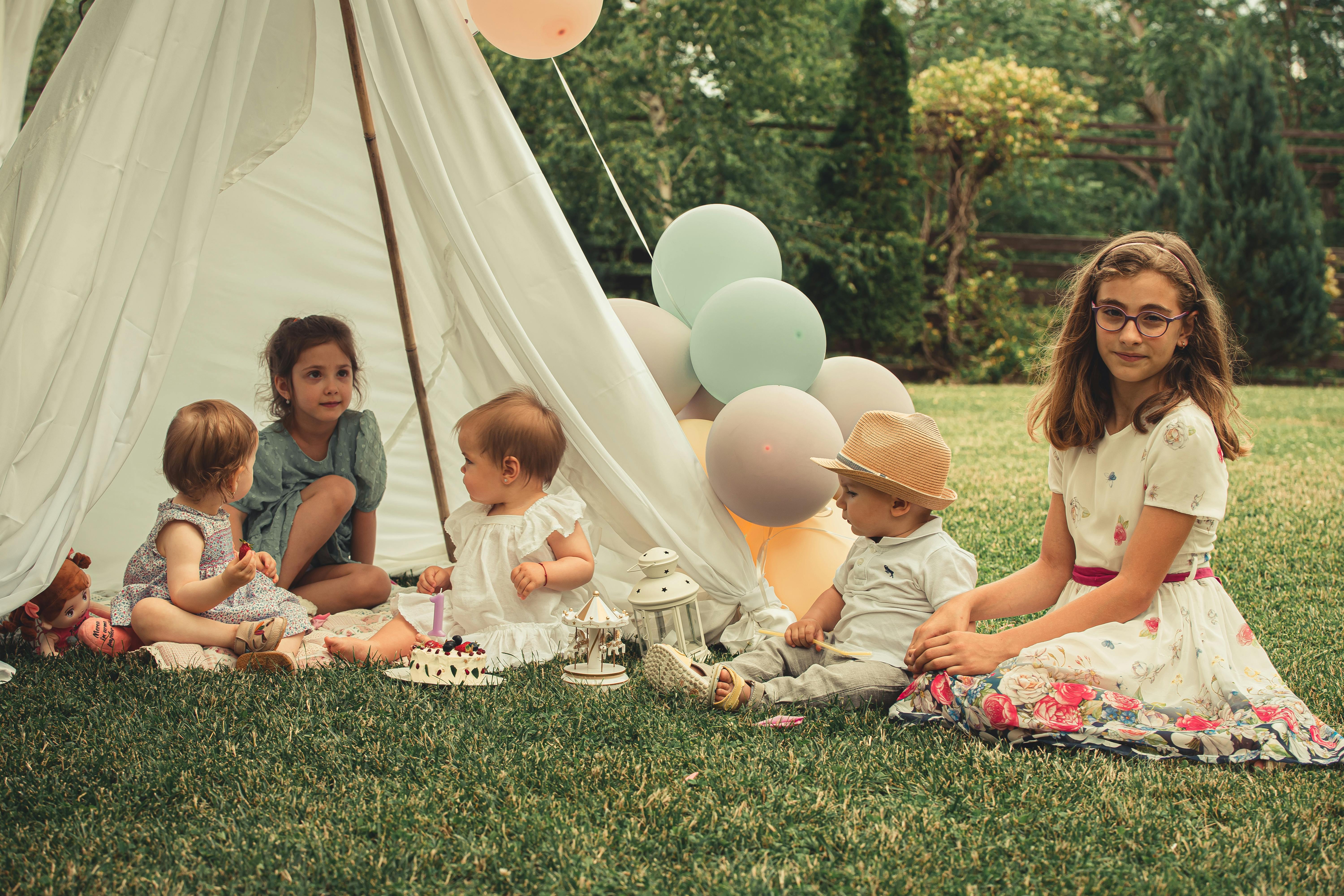 Kids Sitting on a Green Field Near Colorful Balloons · Free Stock Photo