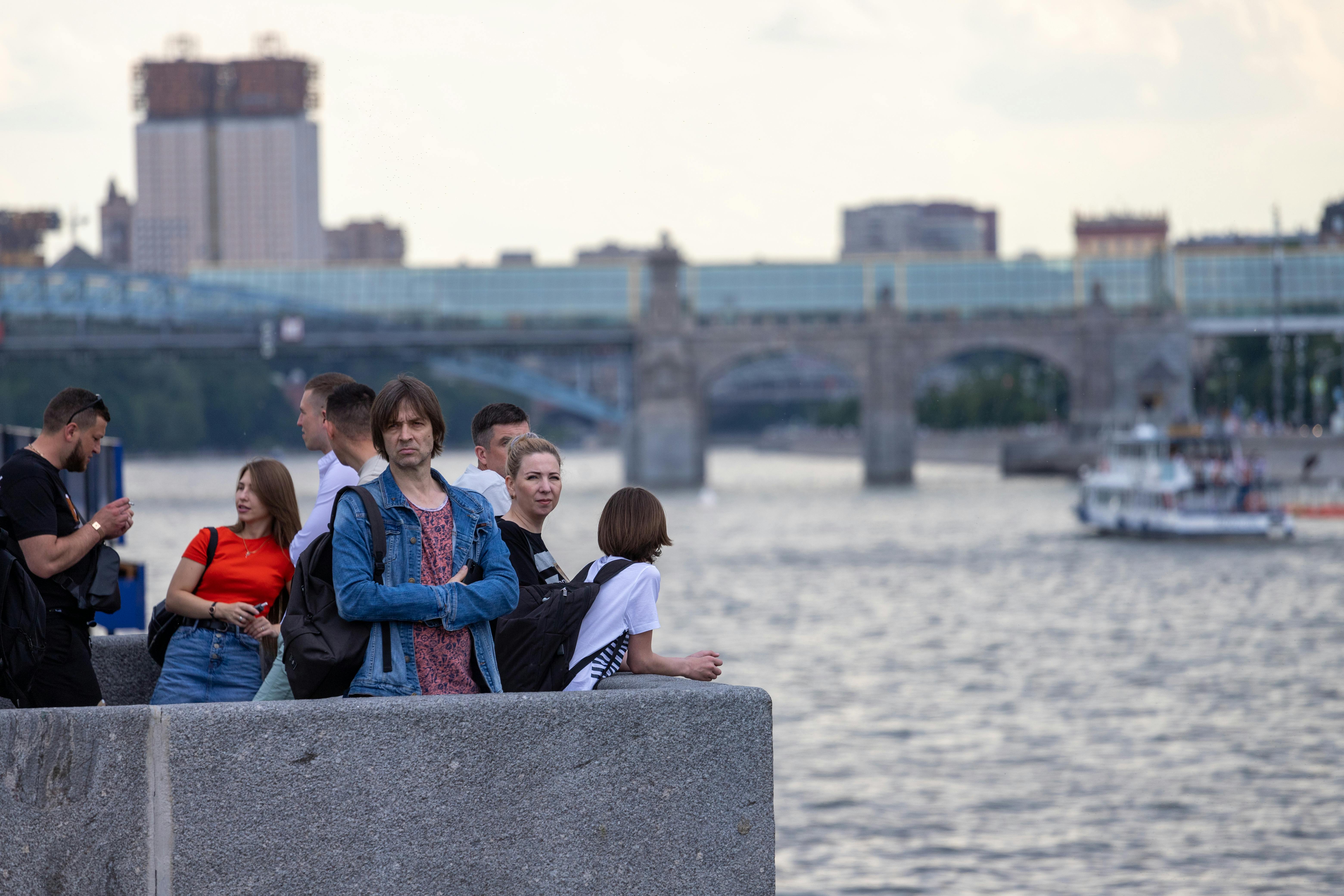 Tourists at a River Bank and Bridge in Background · Free Stock Photo