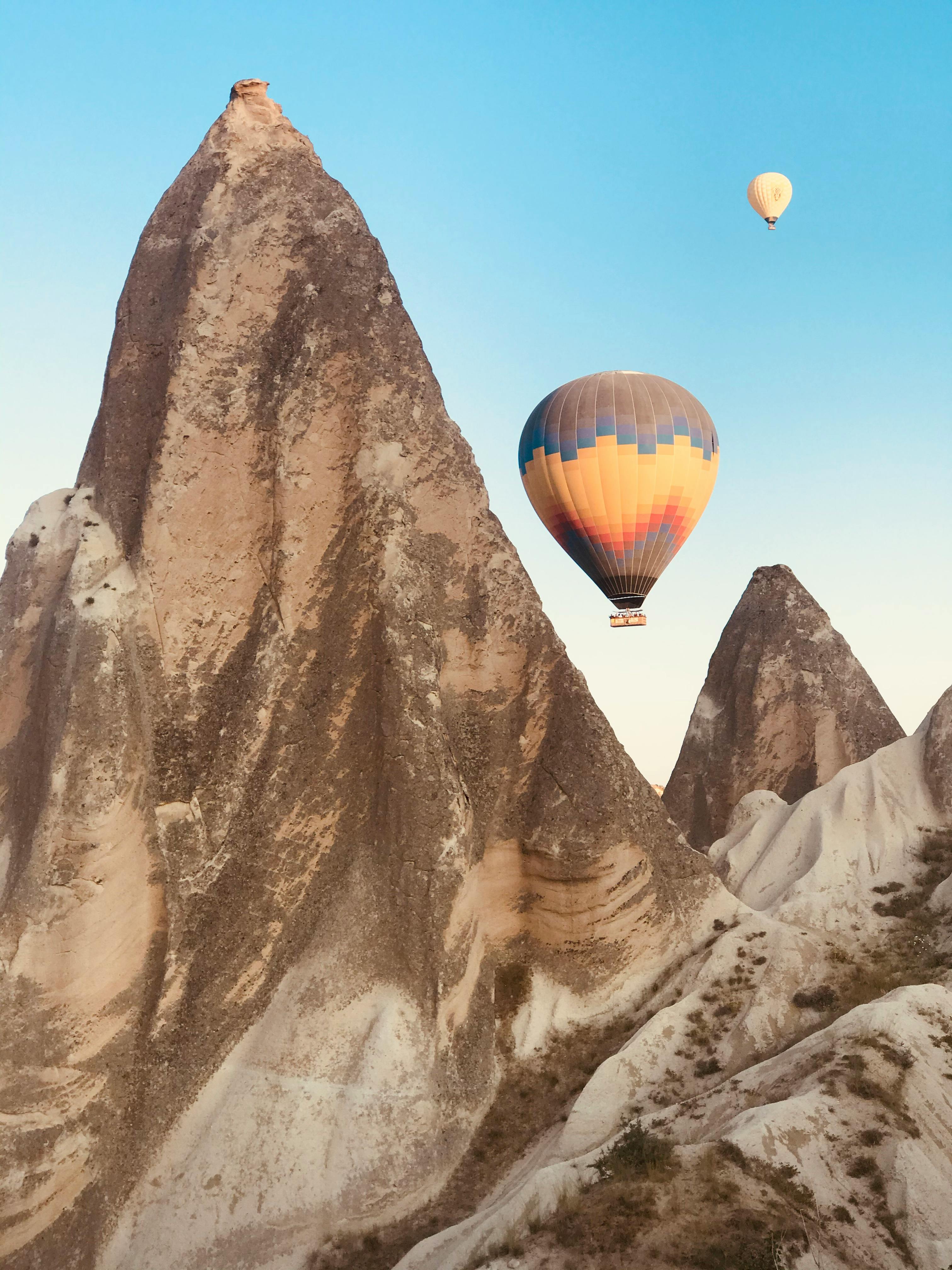 Hot Air Balloons Flying Over a Rocky Mountain · Free Stock Photo