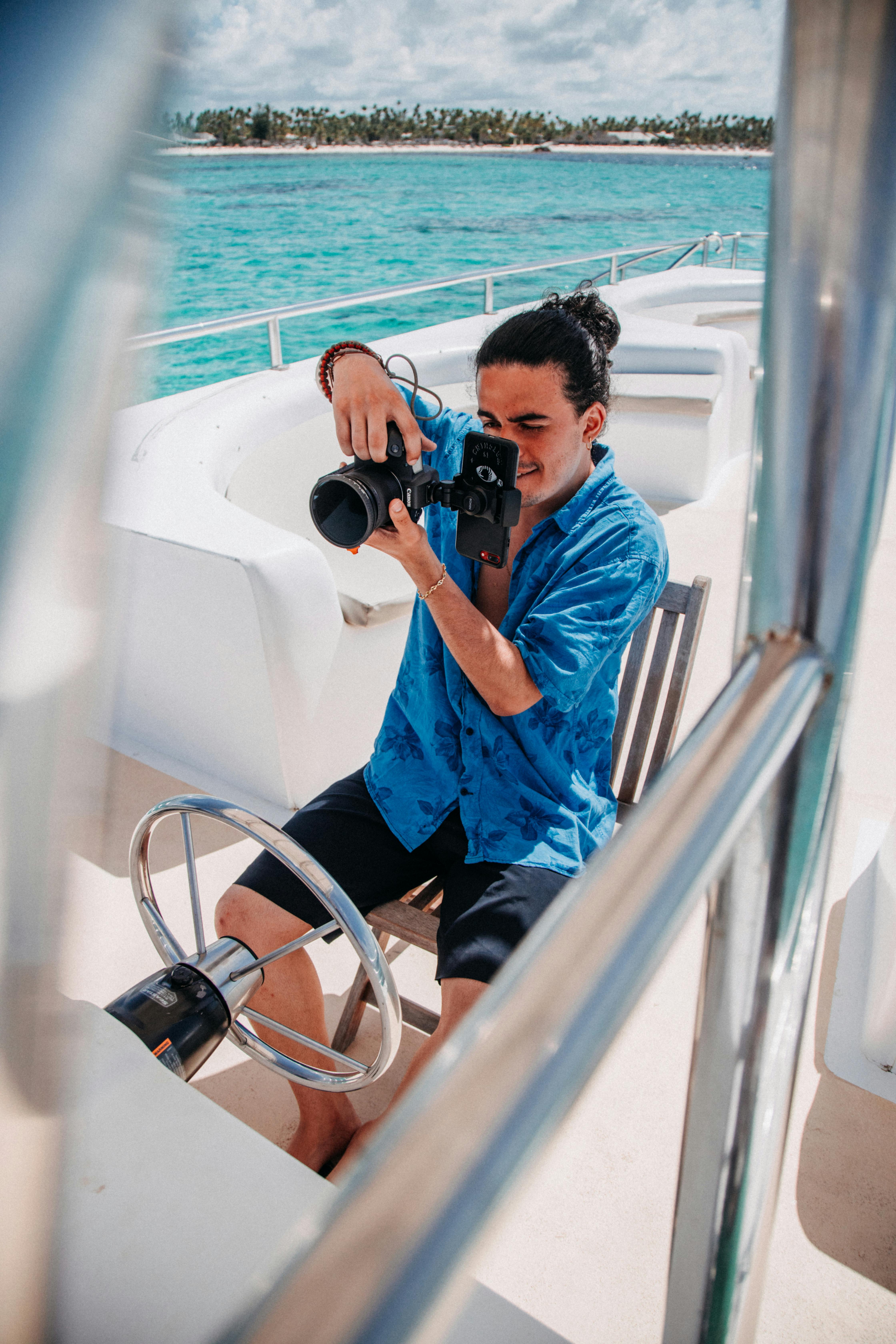 A Man Sitting on the Yacht using a Camera · Free Stock Photo