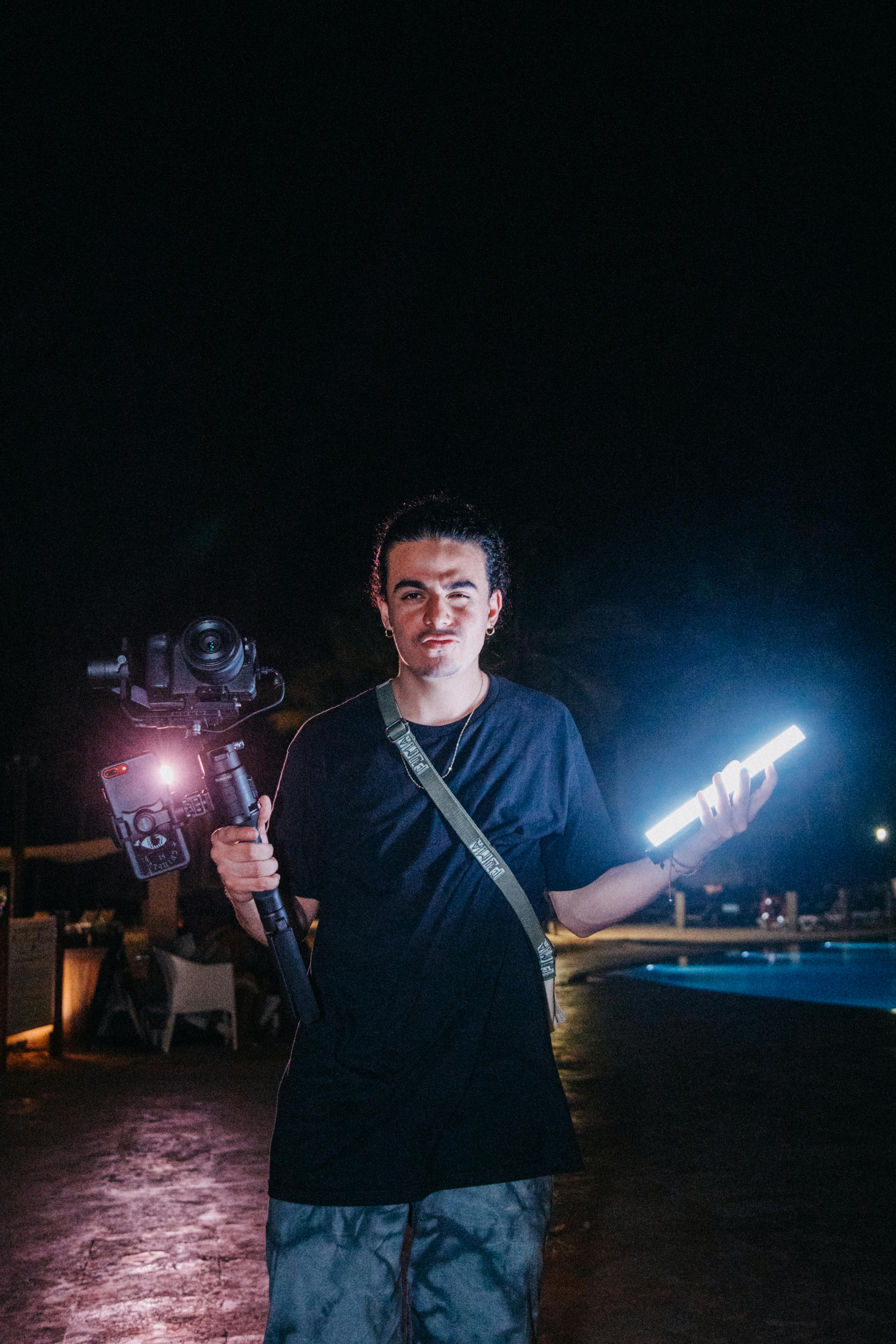 A Man Holding a Video Camera and a Lighted Light · Free Stock Photo