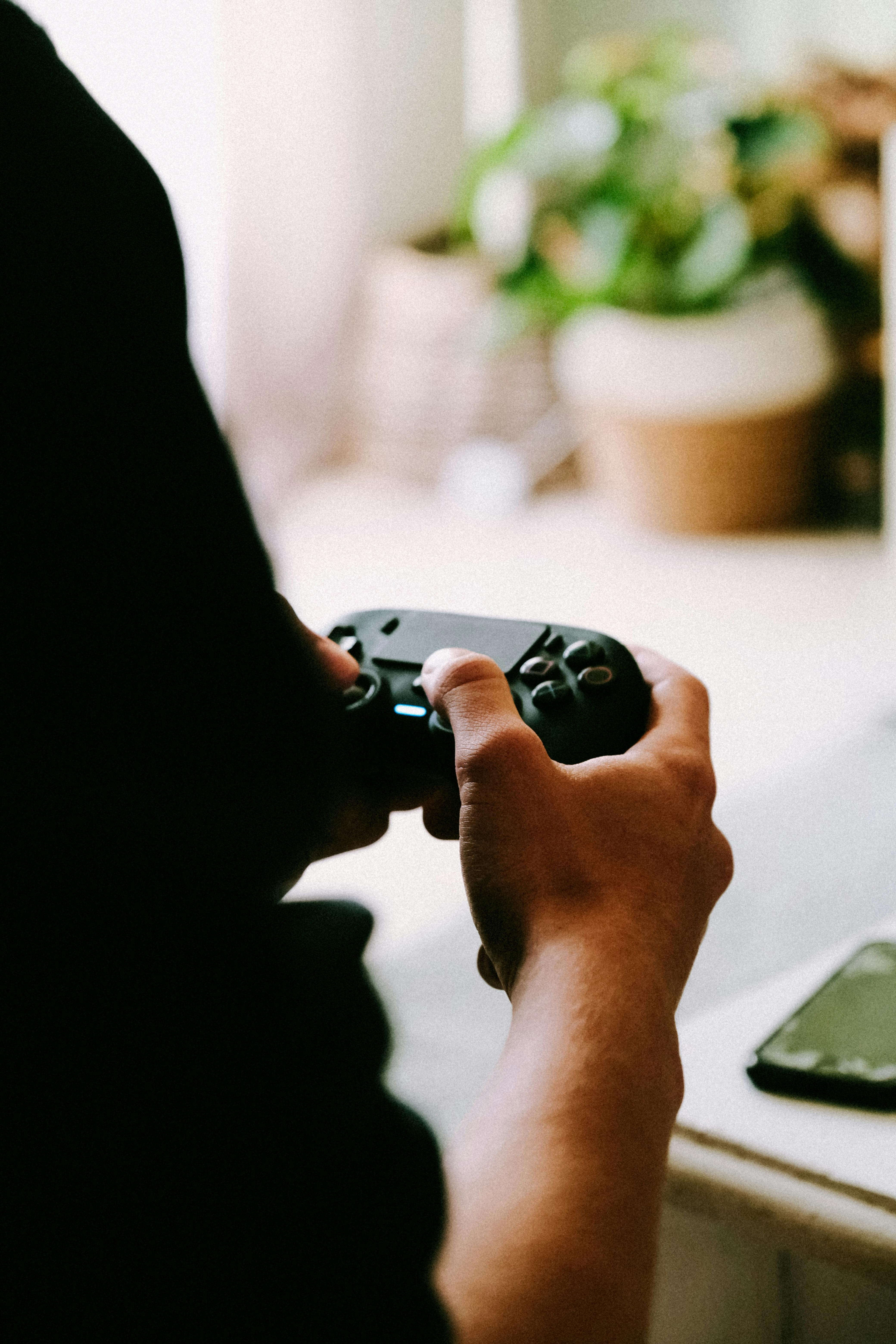 Person Holding a Vintage Game Console Controller · Free Stock Photo