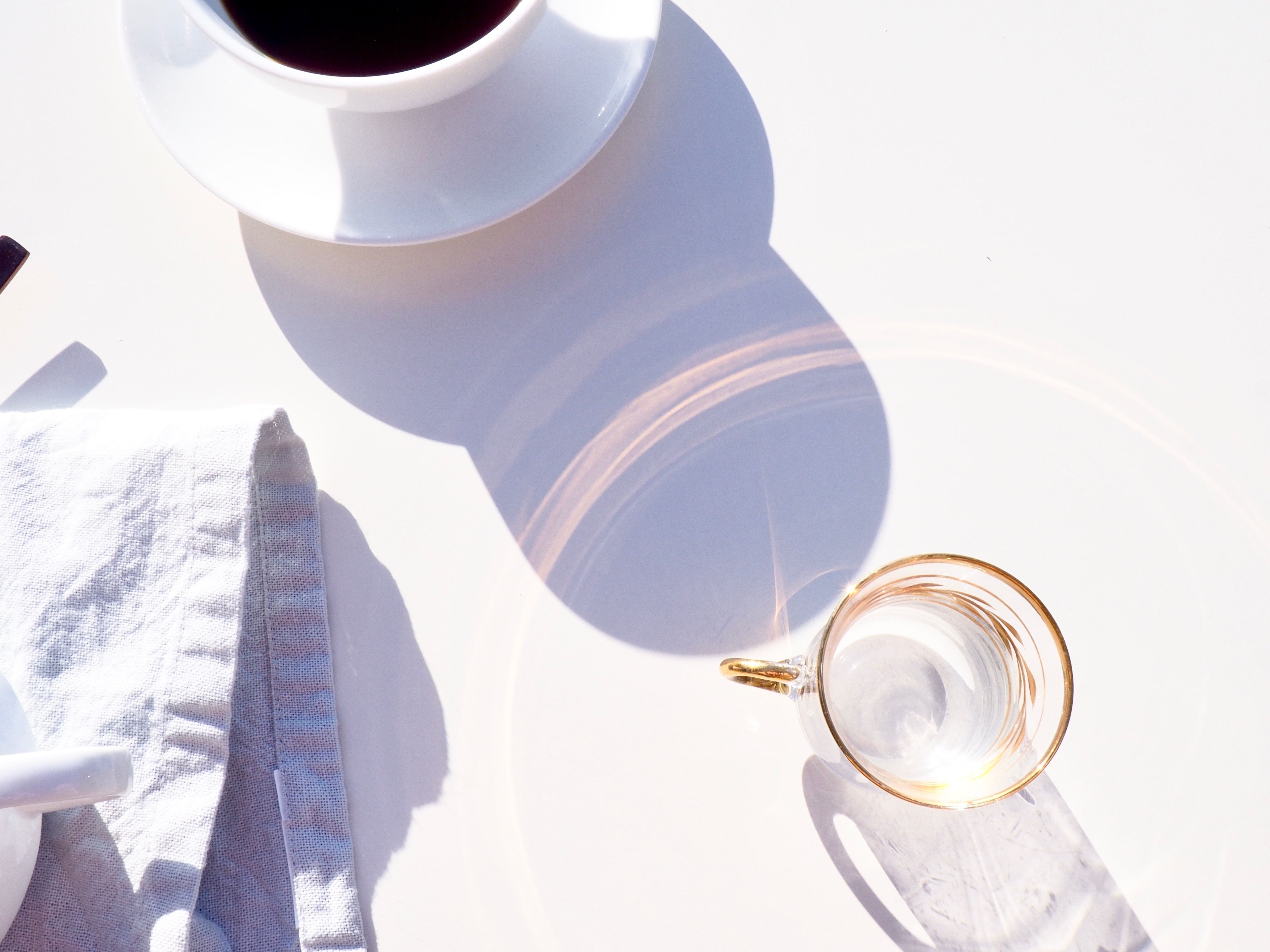 Empty glass reflecting sun near cup of coffee in morning · Free Stock Photo