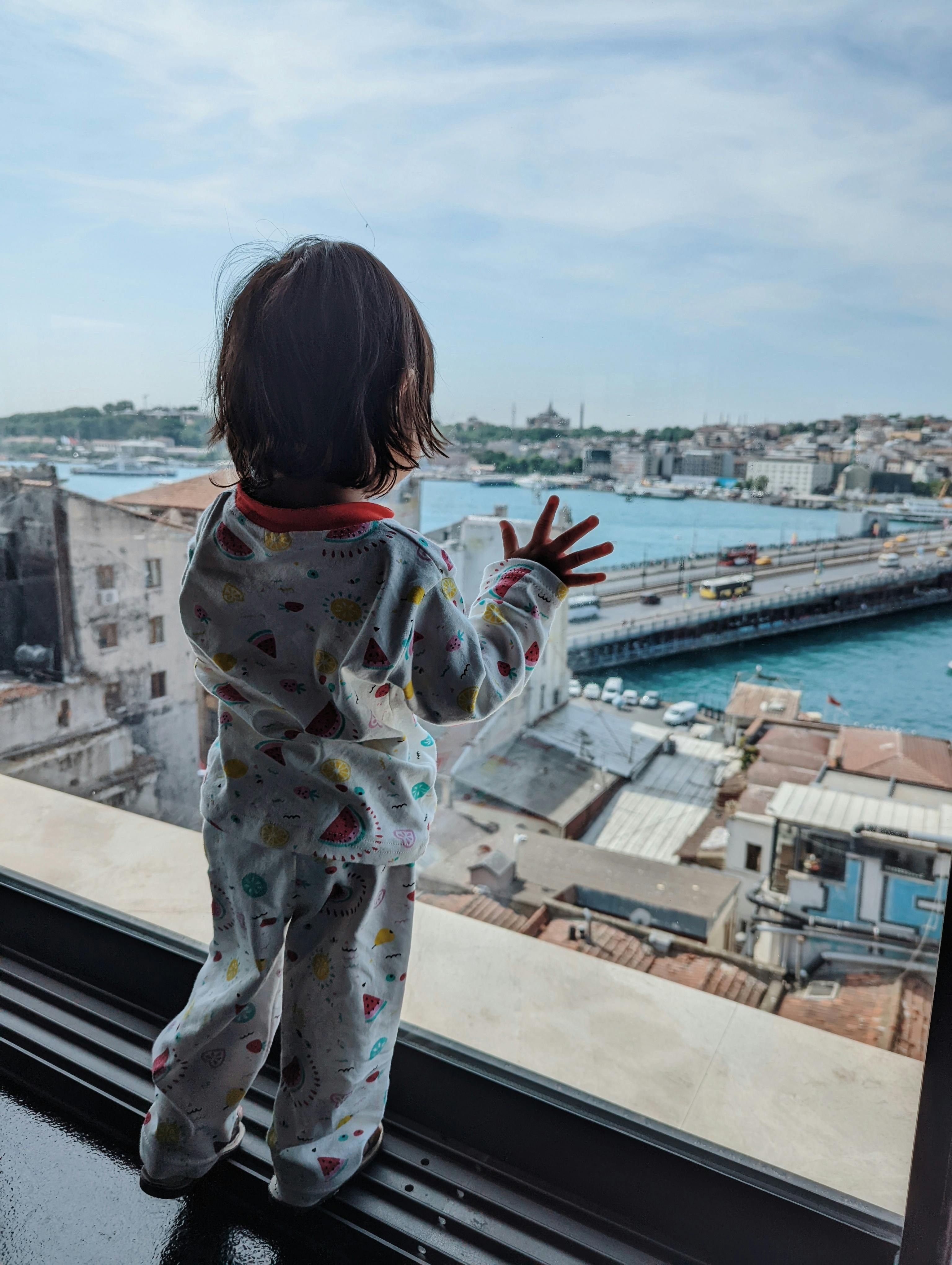 Back View of a Kid Standing Near the Glass Wall · Free Stock Photo