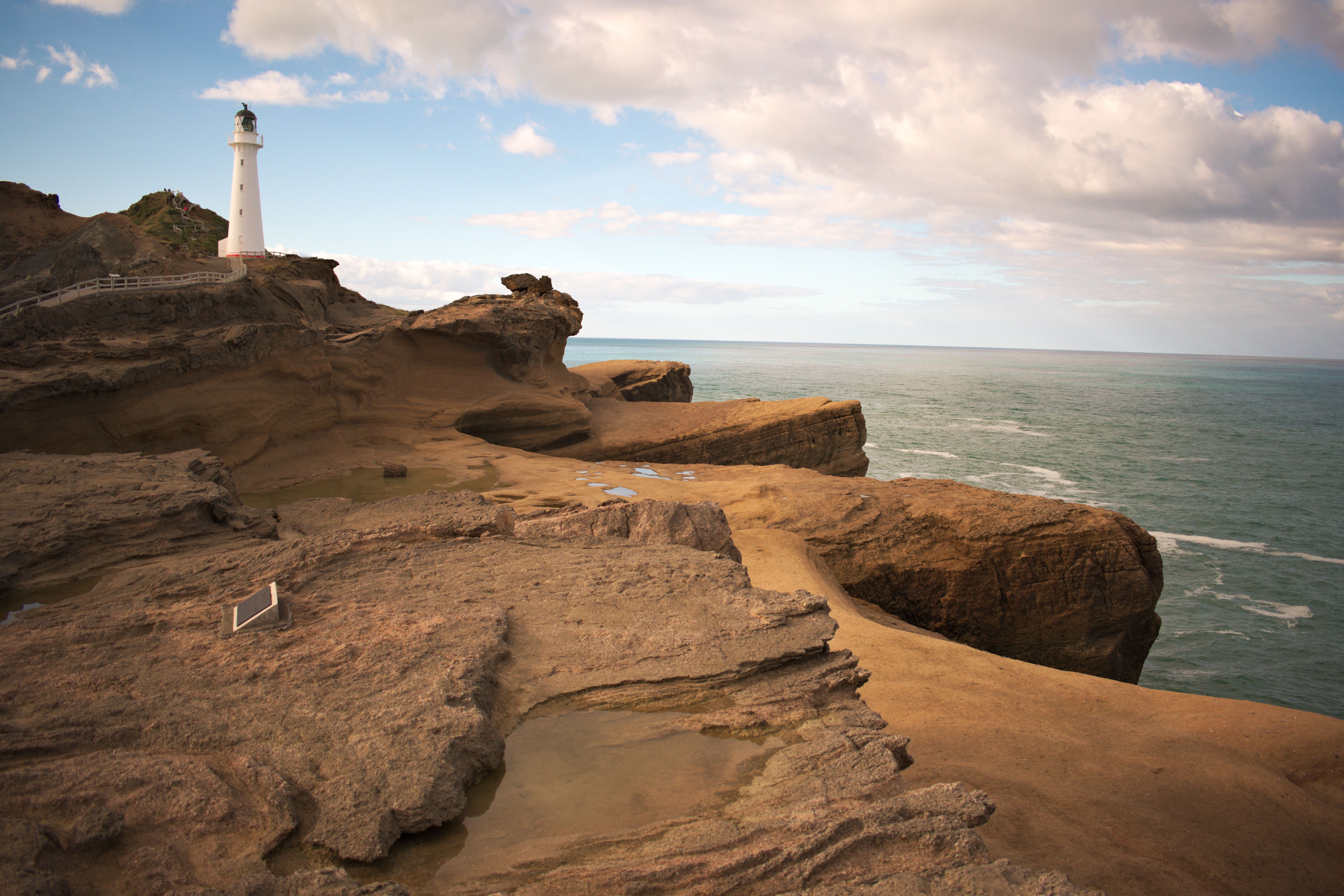 White Lighthouse on Brown Rock Formation · Free Stock Photo