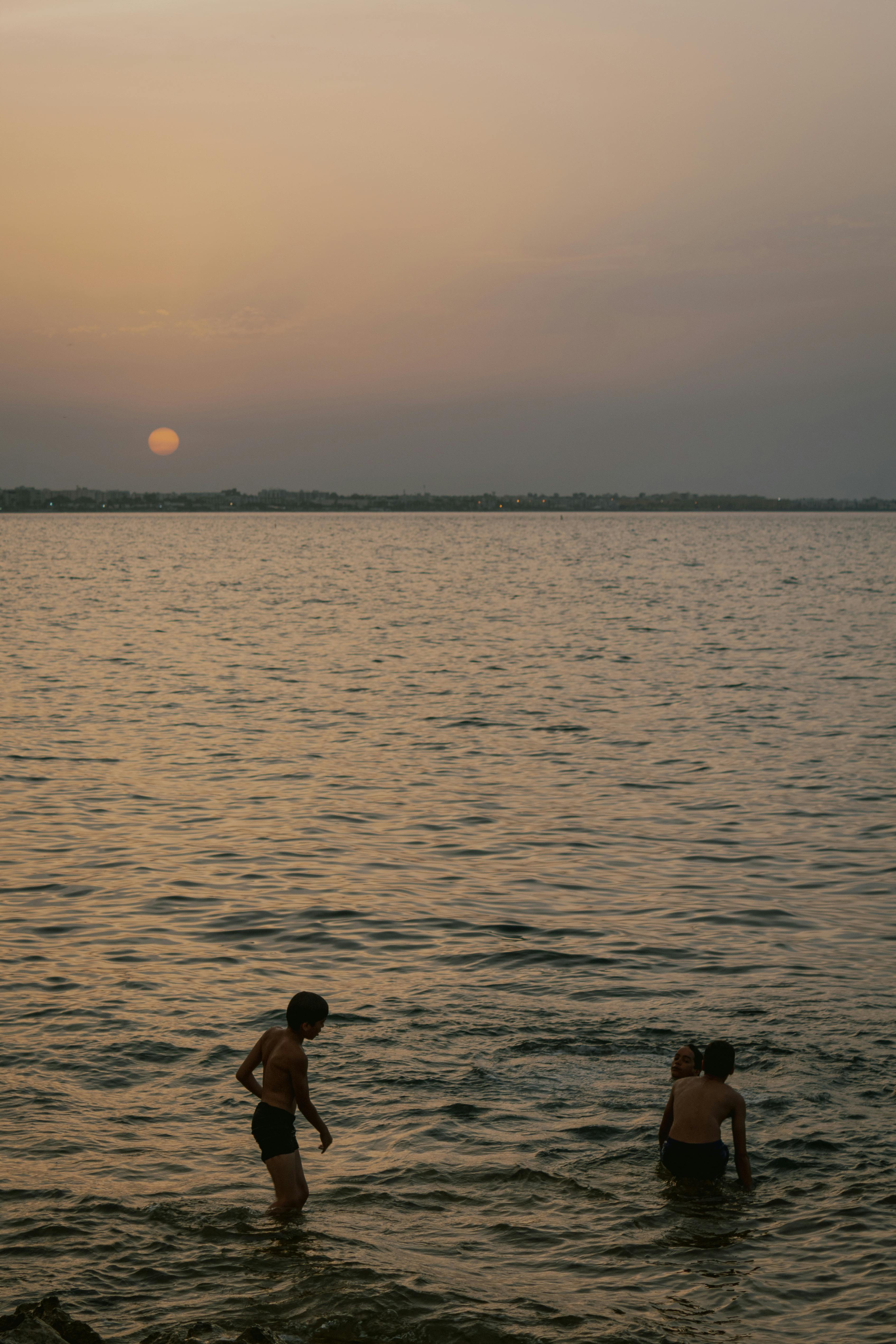 Kids Bathing in a Sea at Dusk · Free Stock Photo