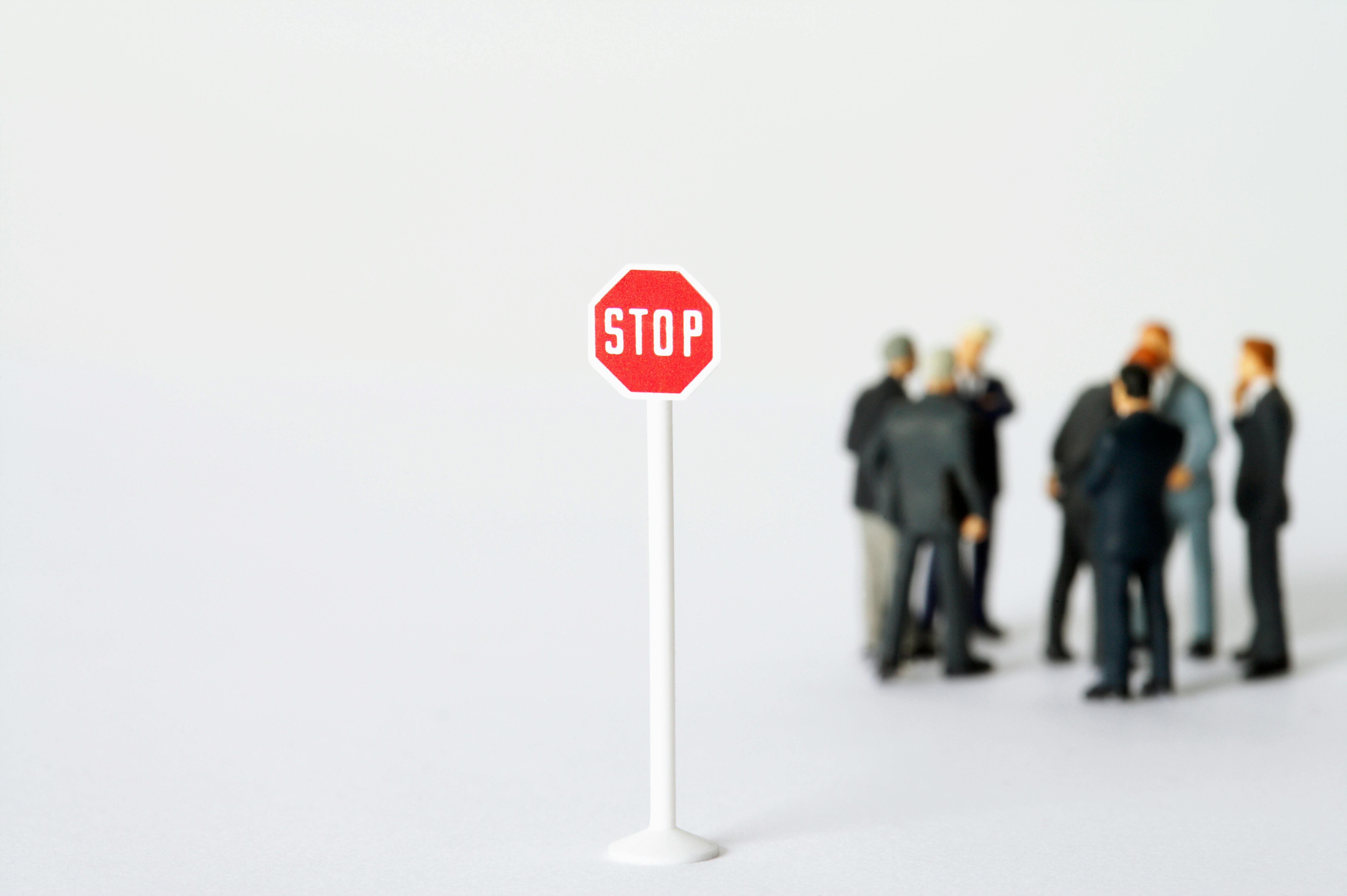 Stop Sign and Figurines of Businessmen Standing Talking · Free Stock Photo