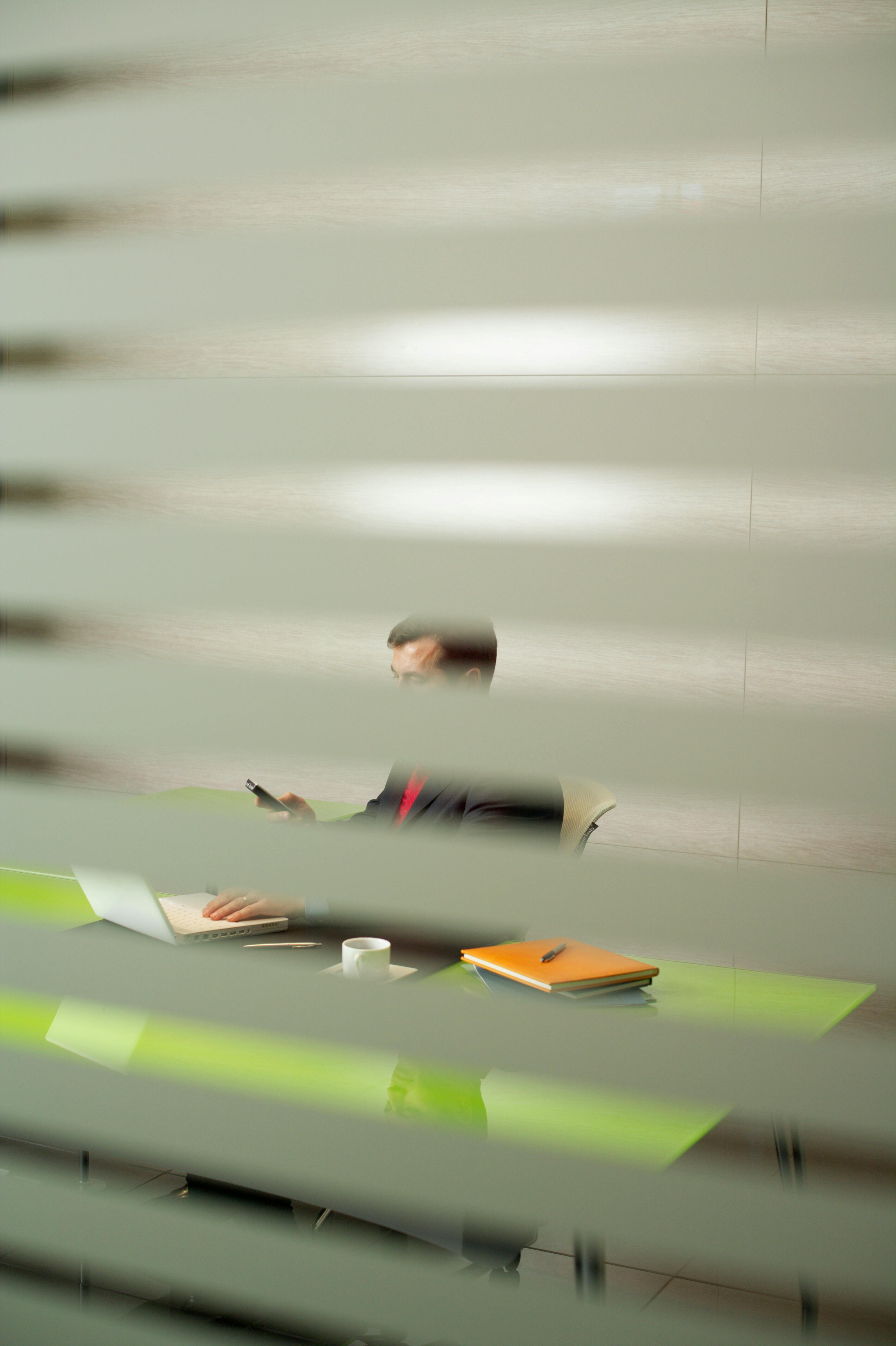 Male Office Worker Seen Through Window Blinds · Free Stock Photo