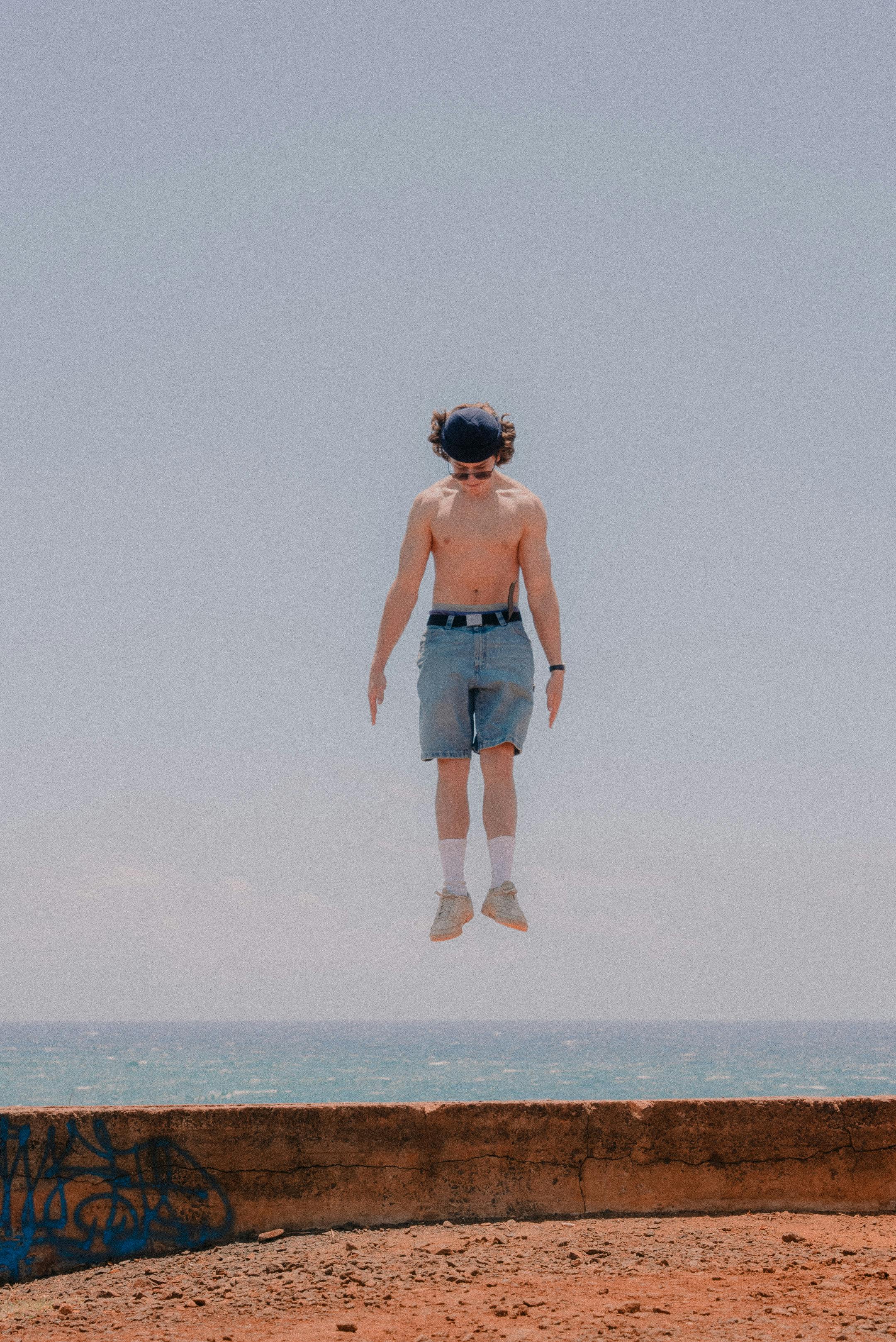 Man Jumping over Wall on Sea Shore · Free Stock Photo