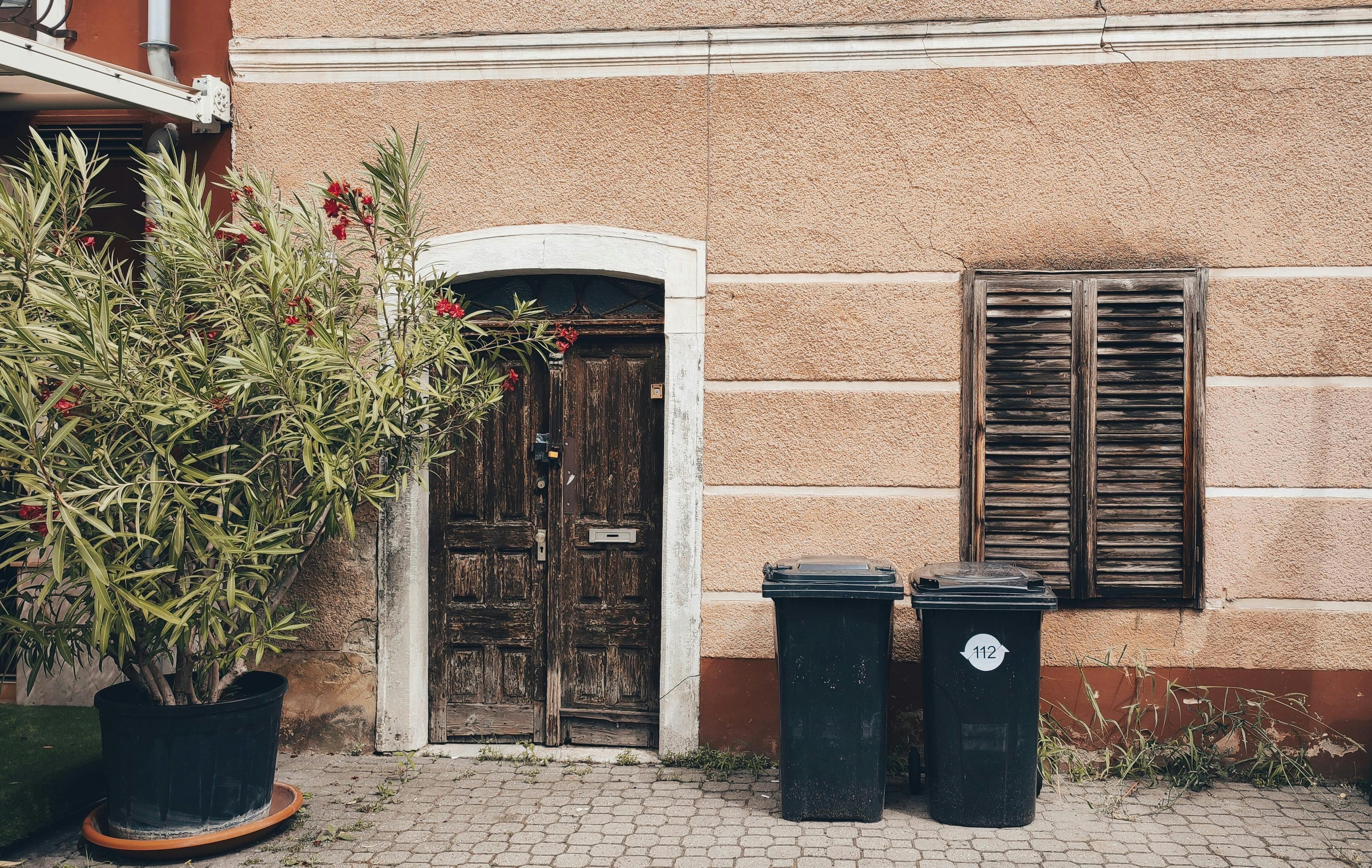 Garbage Bins beside a Wooden Window · Free Stock Photo