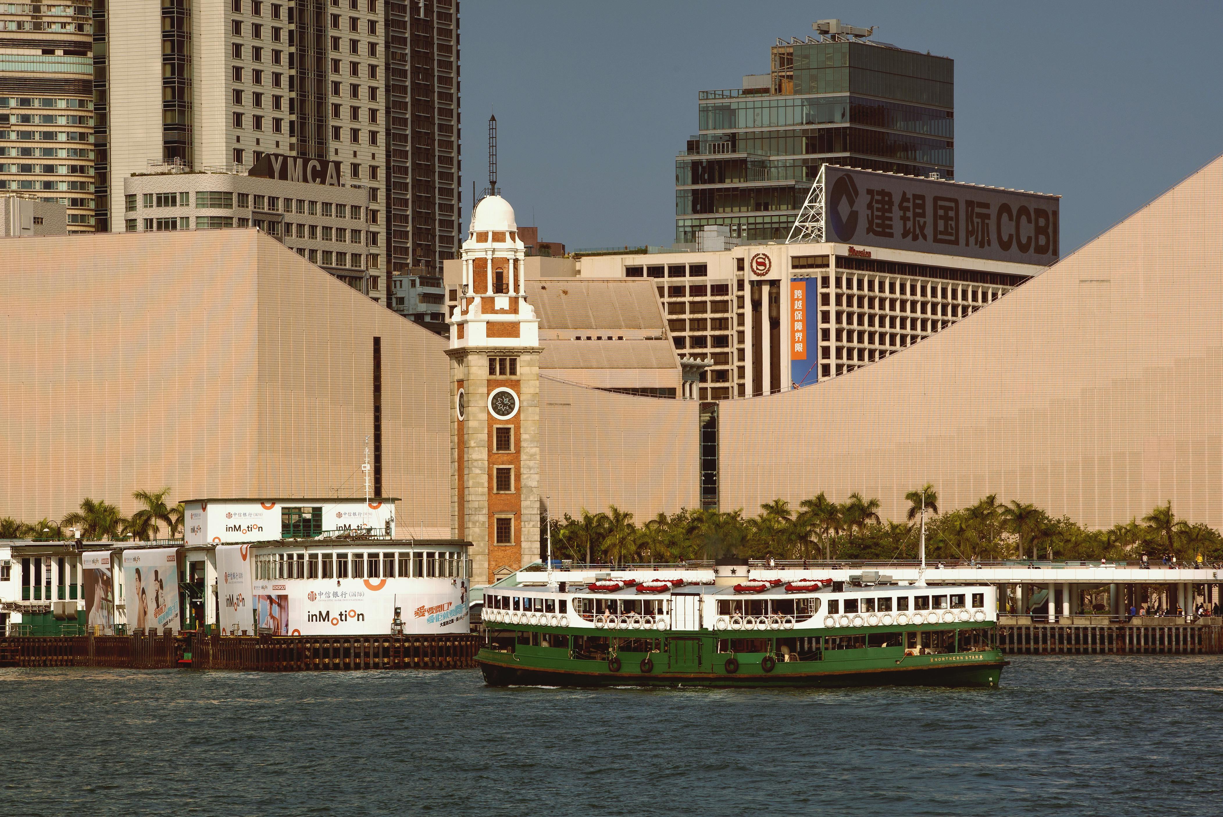 A White and Green Ferry Cruising on River Near a Tower · Free Stock Photo