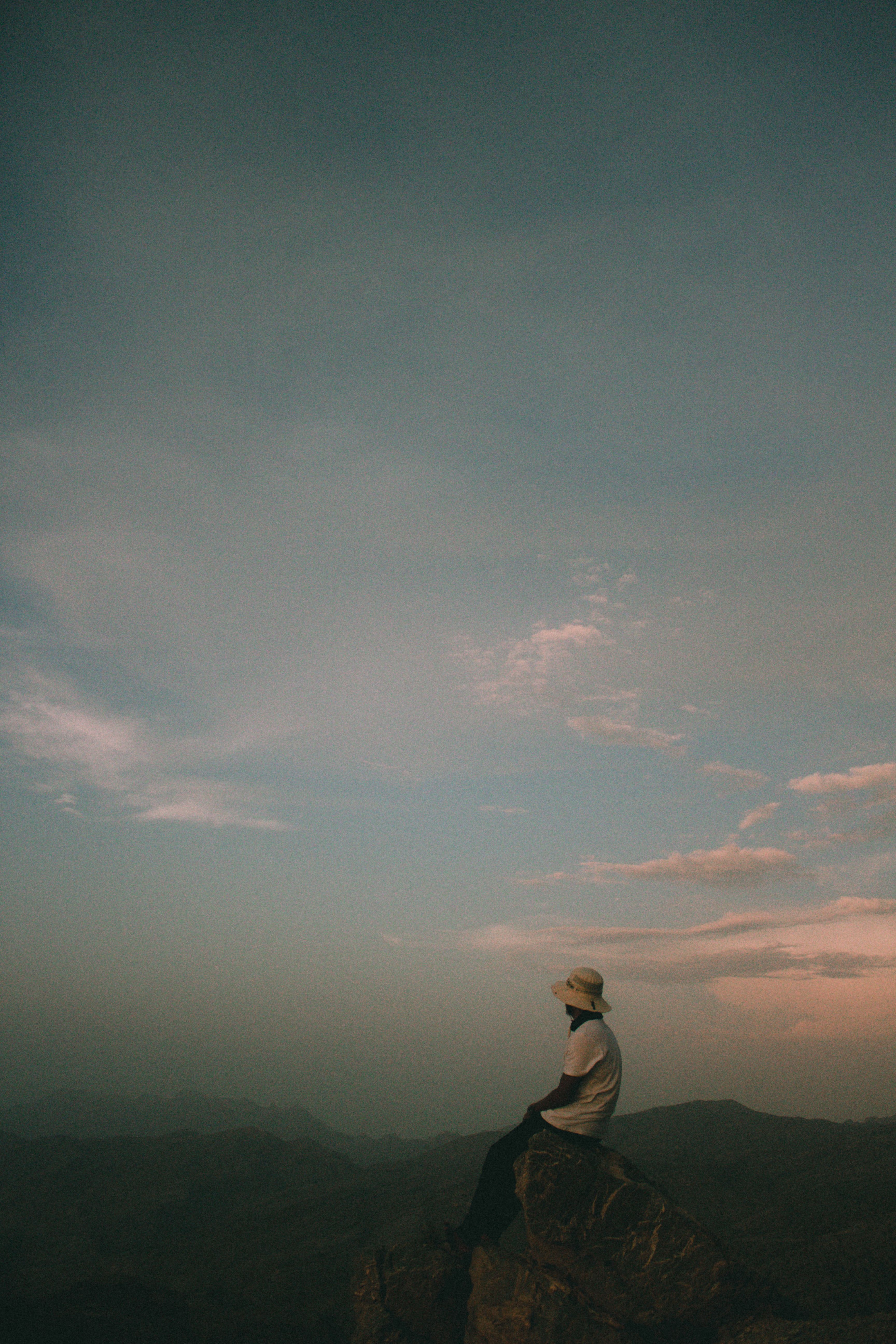 Person Wearing Hat Sitting on Rock Formation · Free Stock Photo