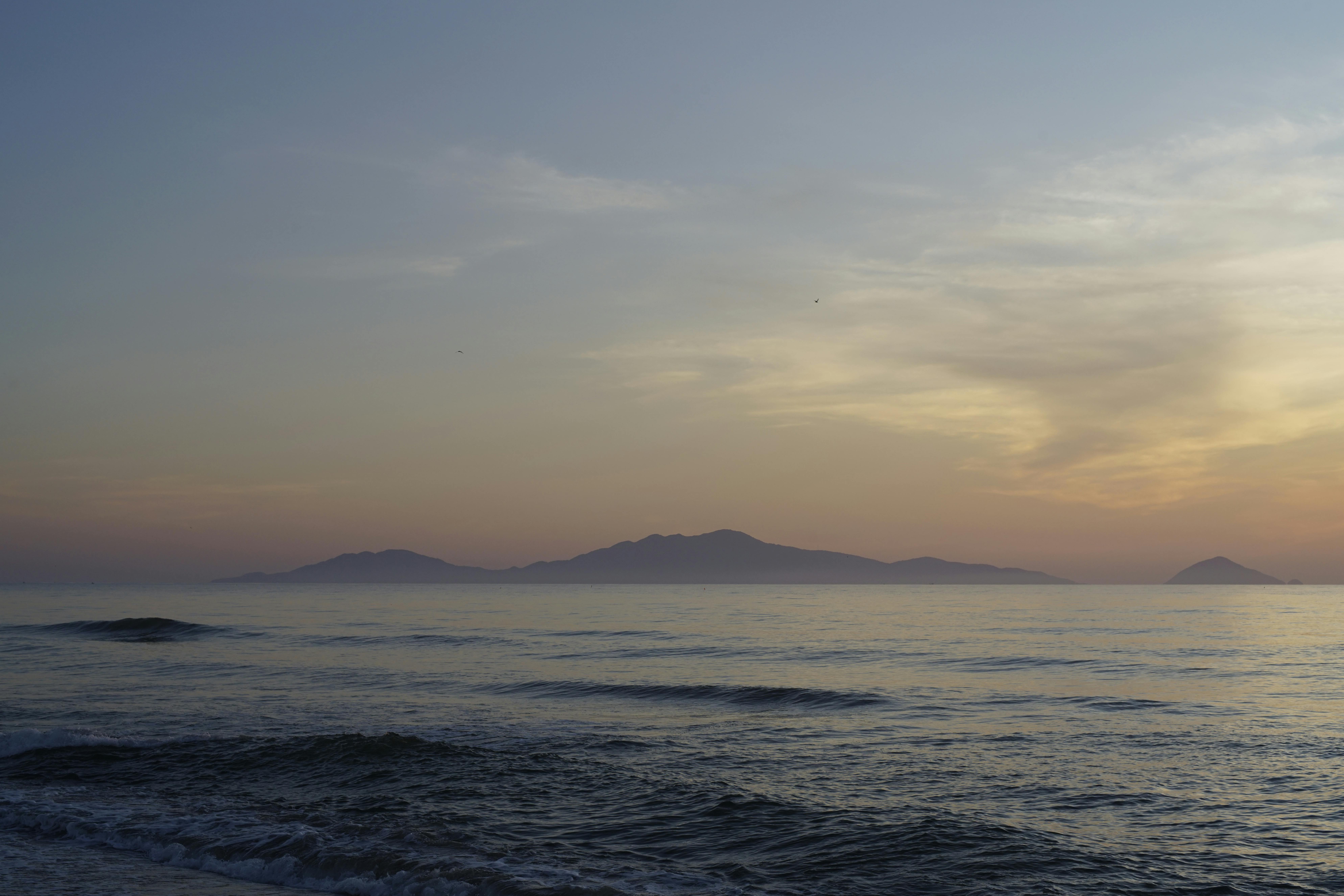 Photograph of an Ocean Near a Mountain · Free Stock Photo