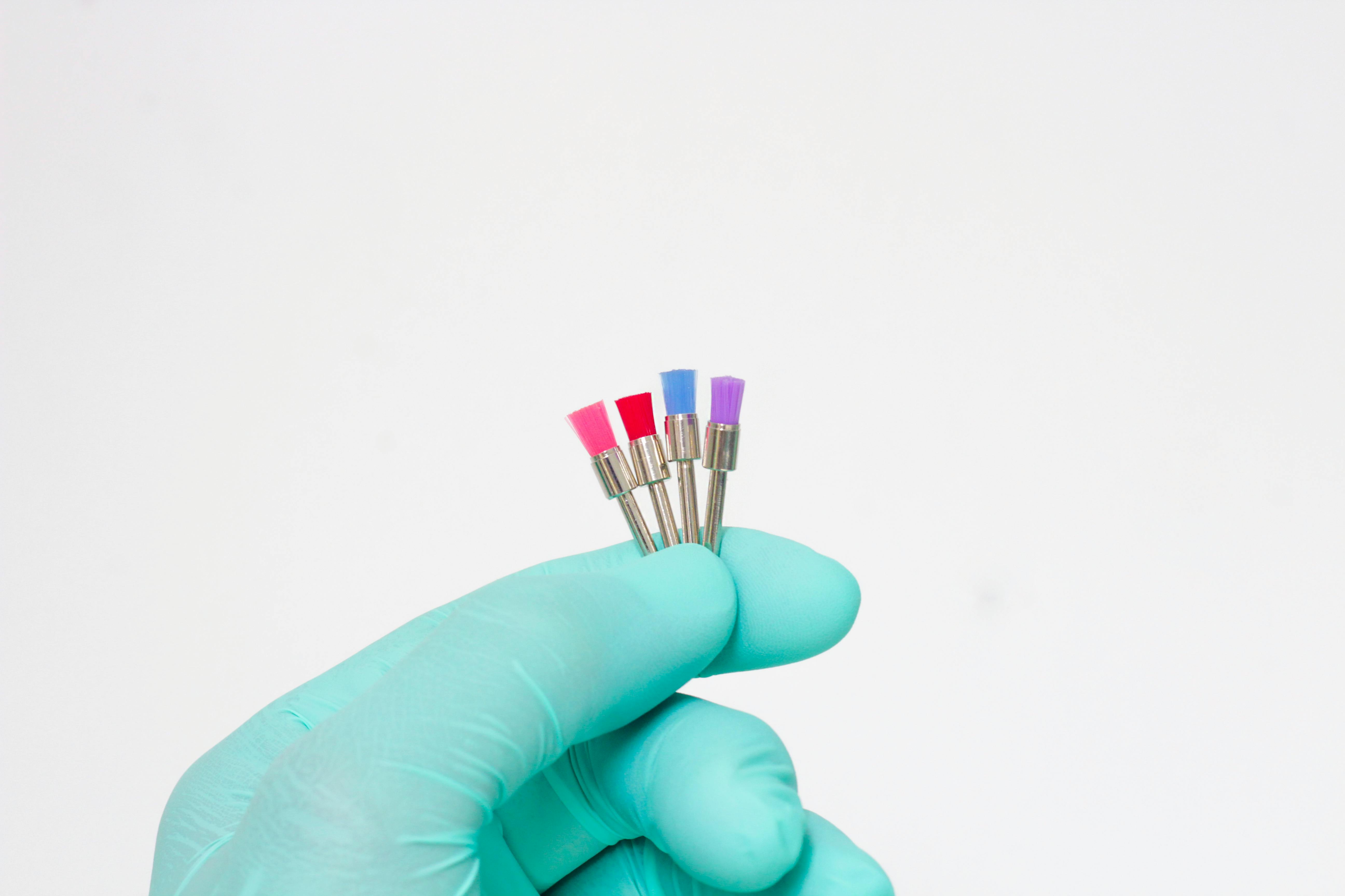 Hand in Glove Holding Colorful Dentistry Brushes · Free Stock Photo