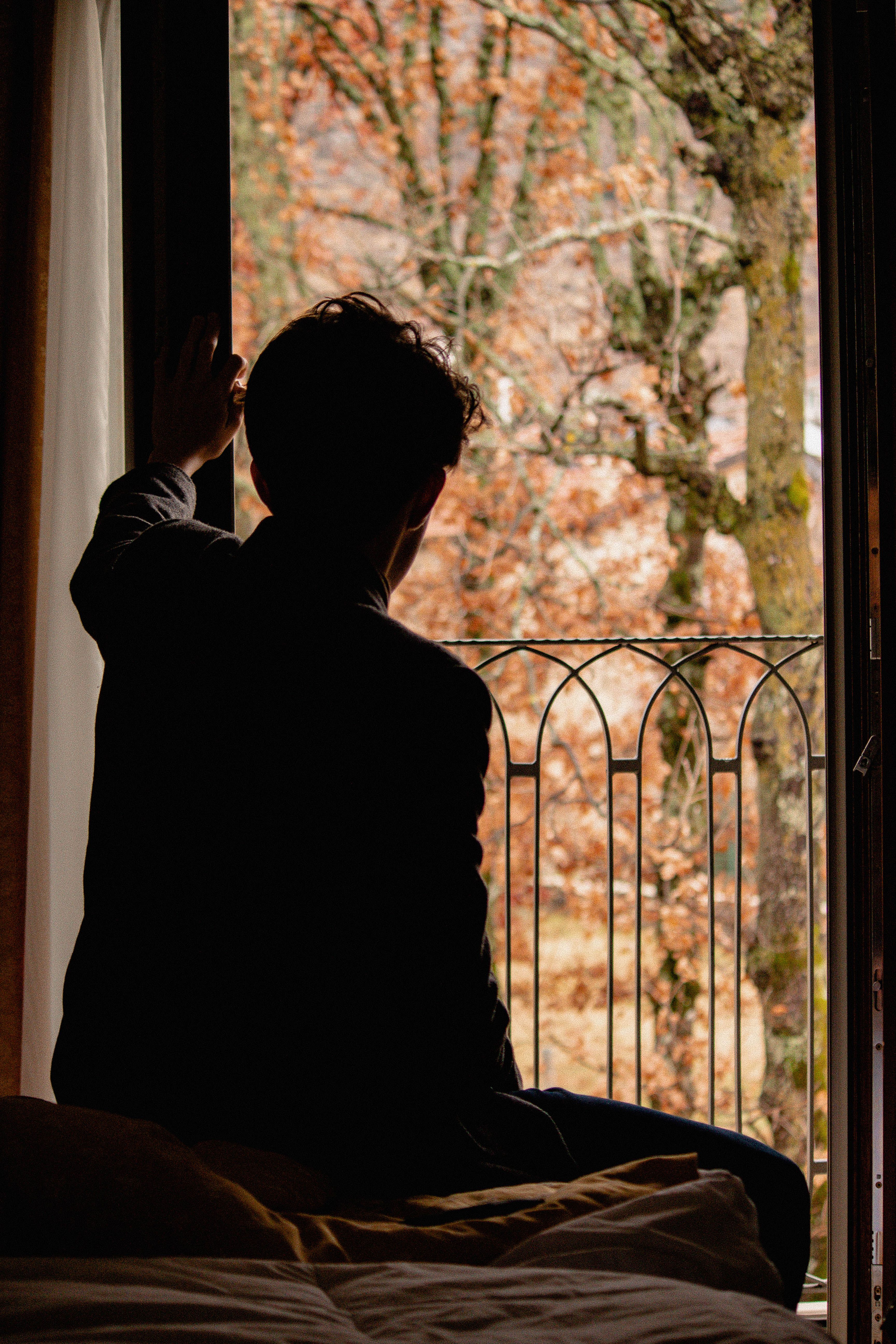 Man Sitting on Bed Beside the Window · Free Stock Photo