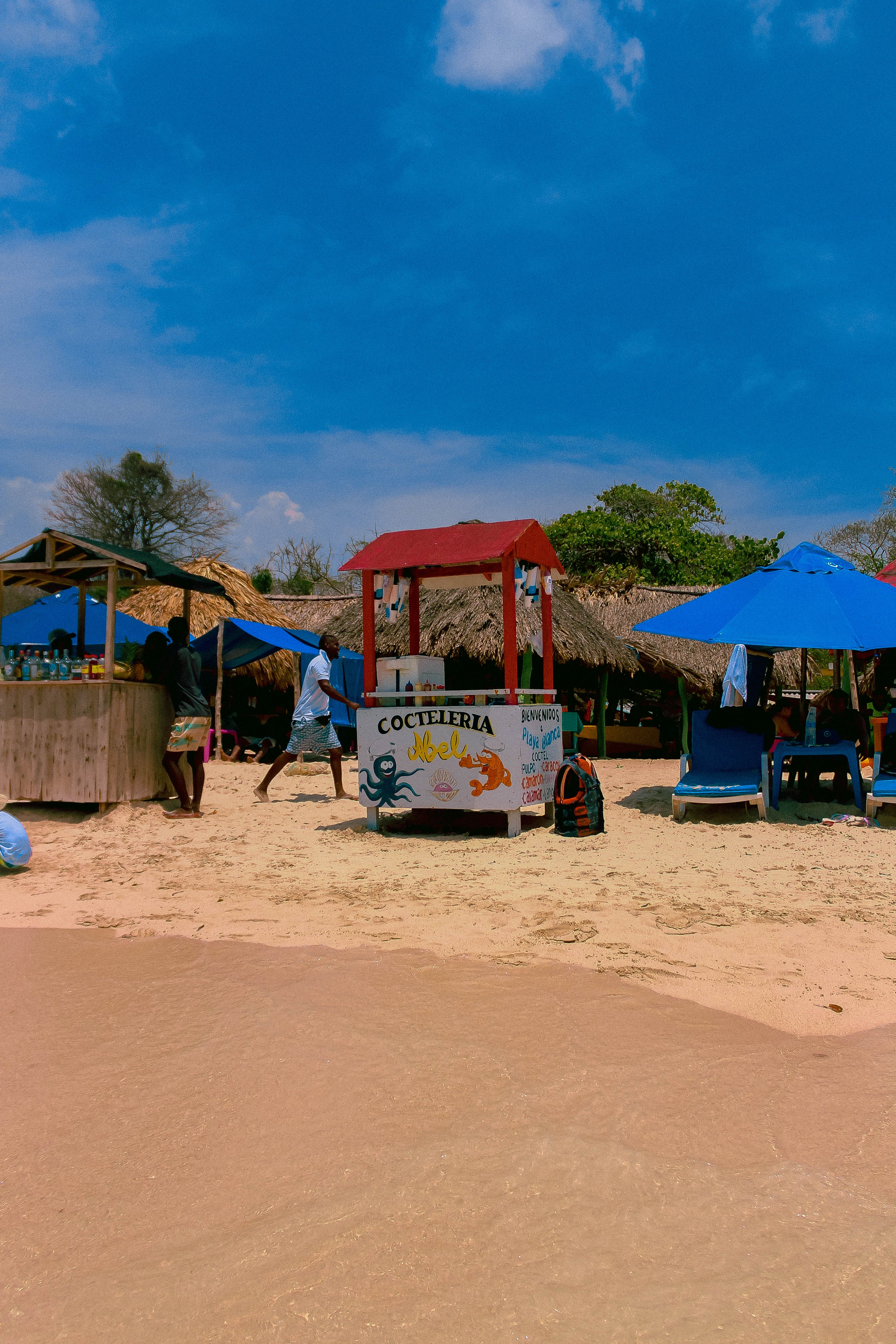 Food Cart and Huts on Sand Under a Blue Sky · Free Stock Photo