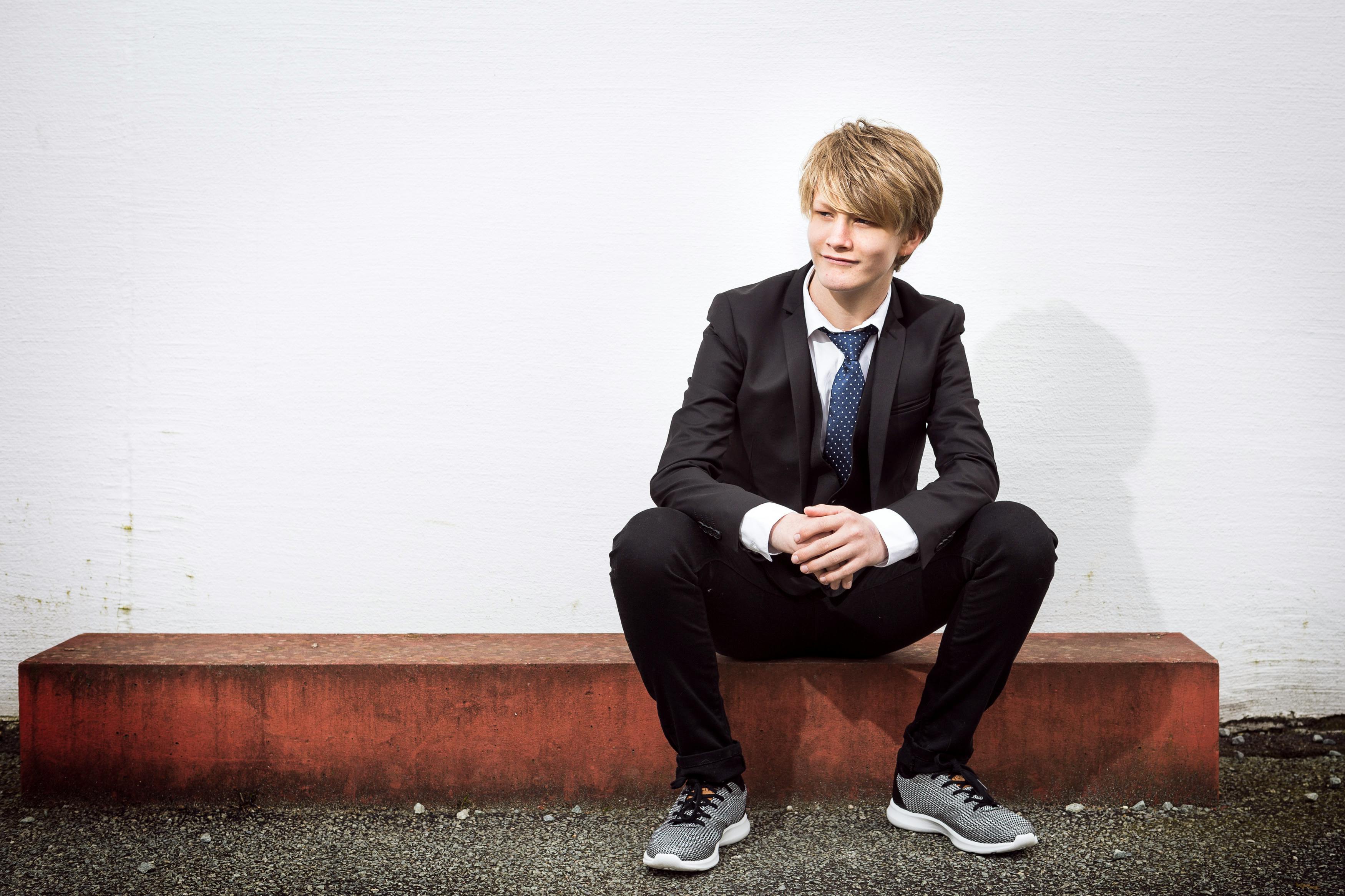 Well-Dressed Boy Sitting in Front of a White Wall · Free Stock Photo