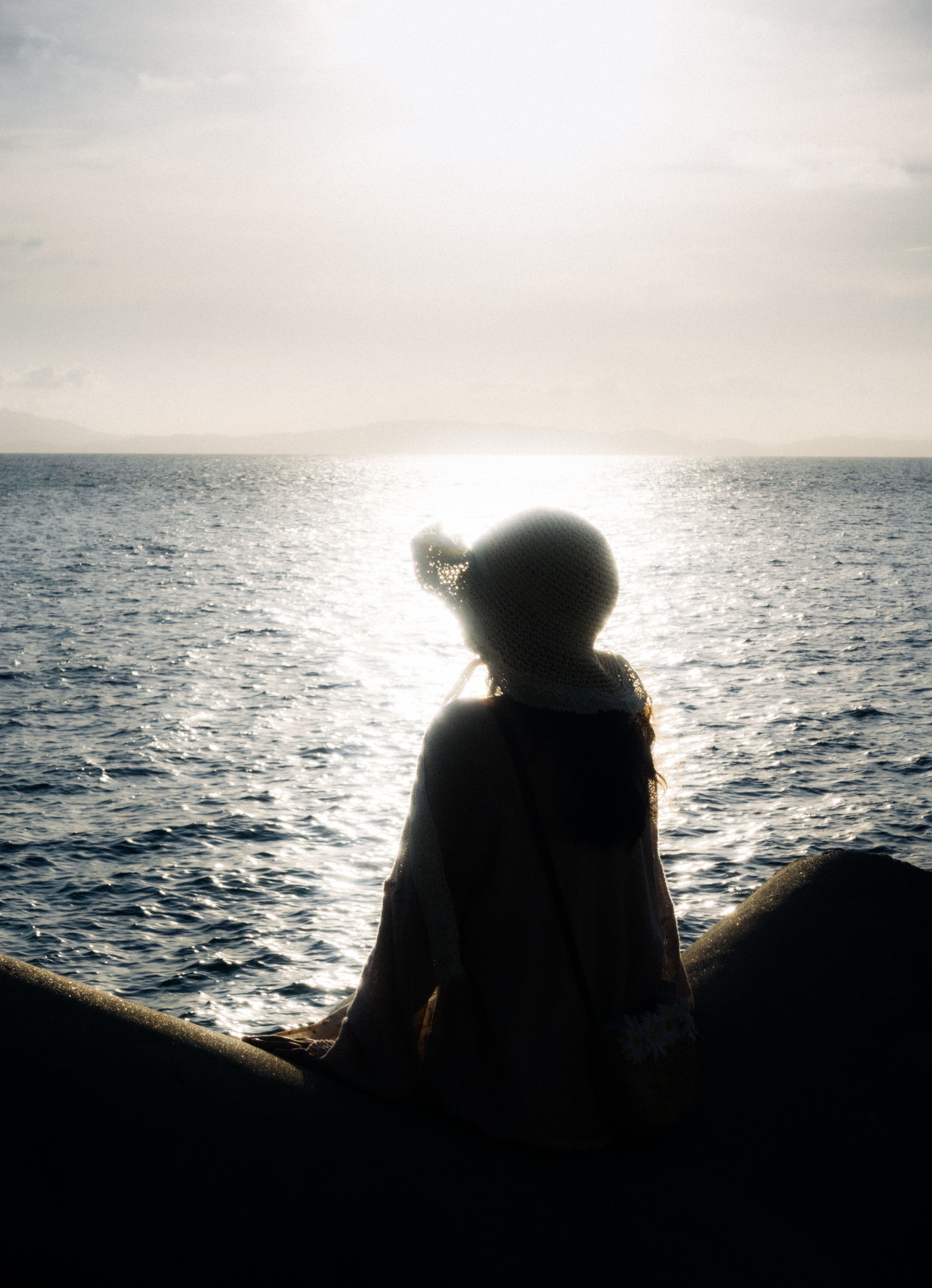 Back View Shot of a Woman Sitting on Big Rocks Near the Sea · Free ...