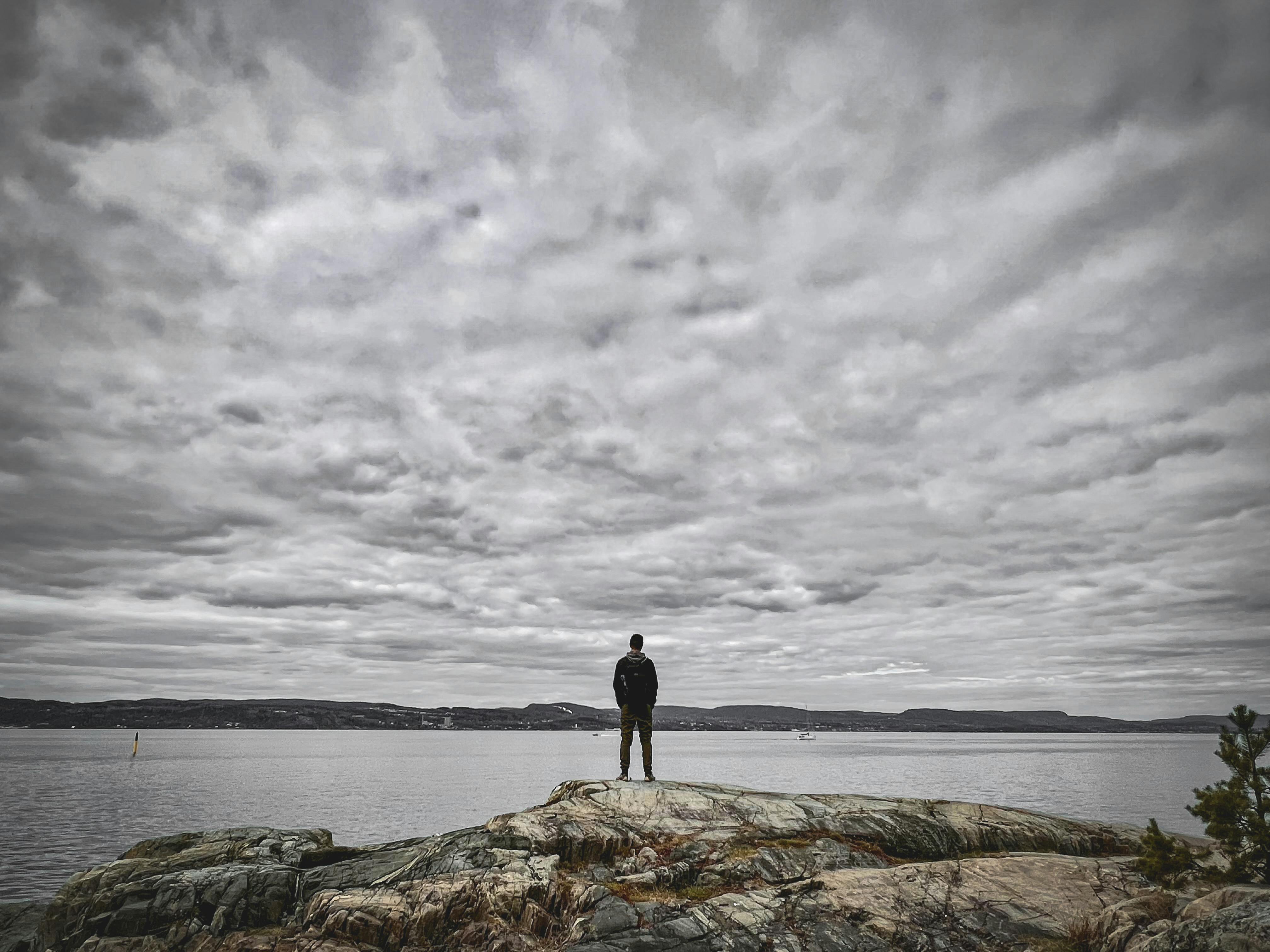 Back View of a Man Standing on a Rock by the Lake · Free Stock Photo