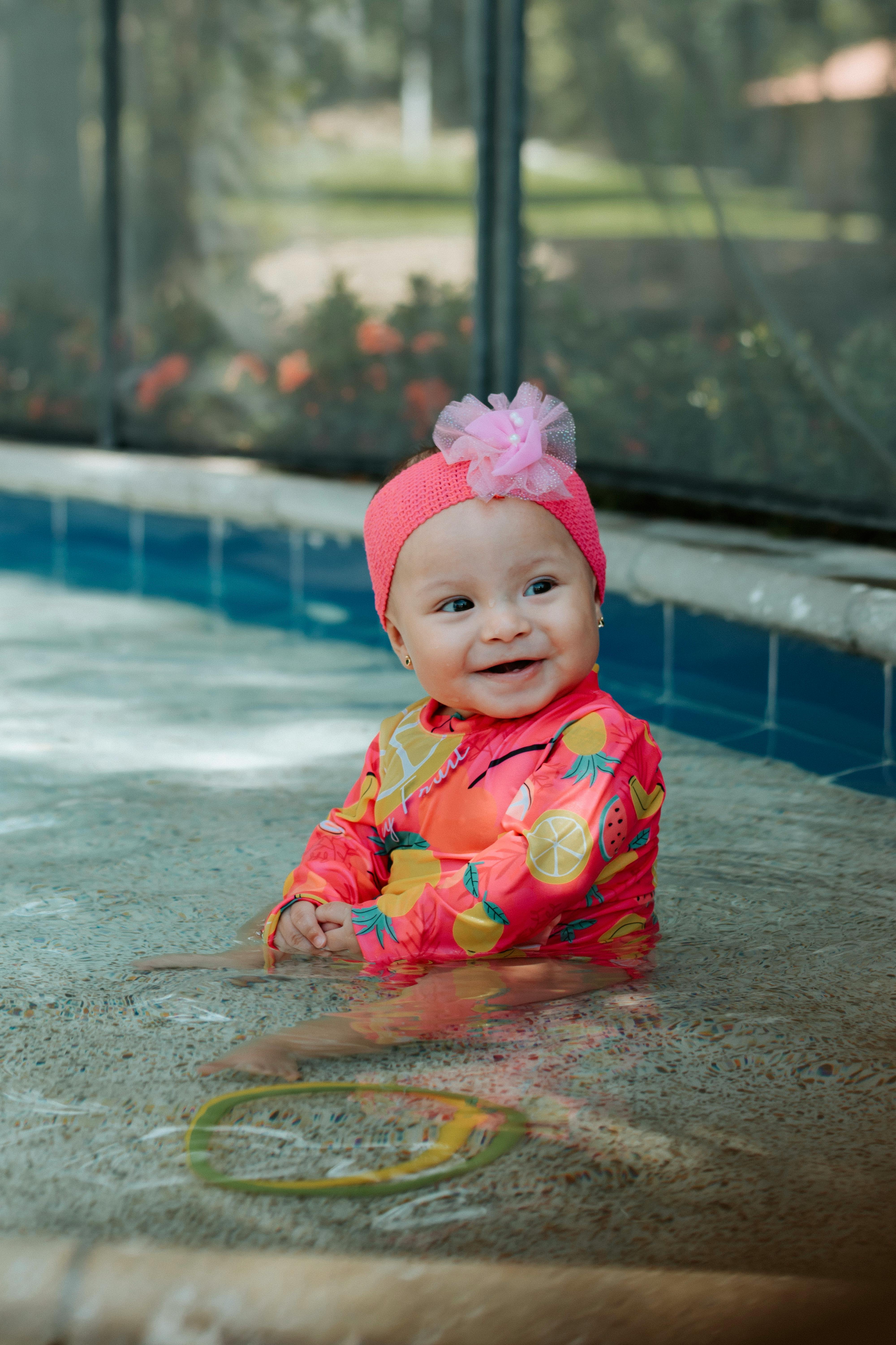 A Baby in Pink Swimwear Sitting on Pool · Free Stock Photo