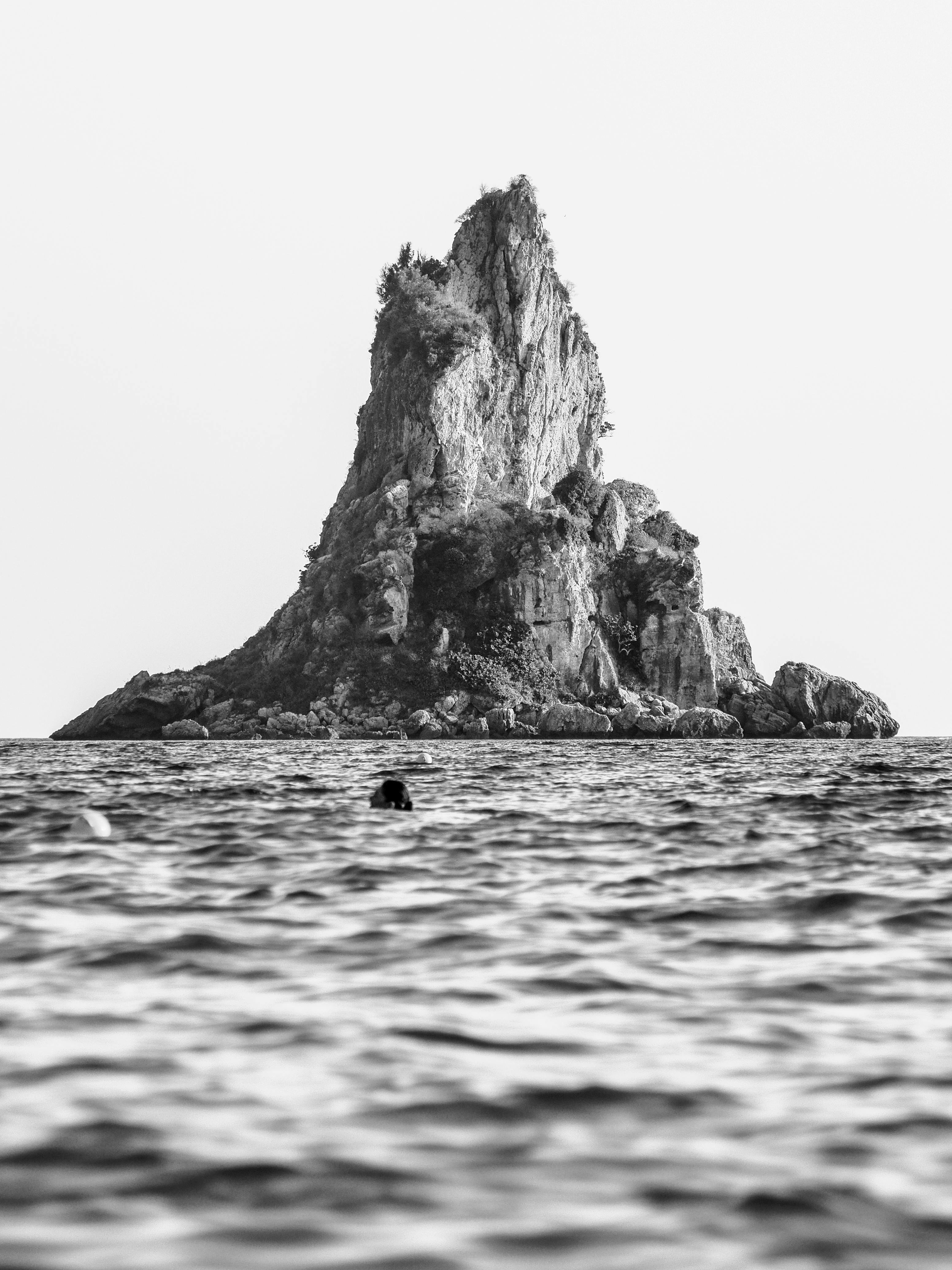 Grayscale Photo of Rock Formations on Body of Water · Free Stock Photo