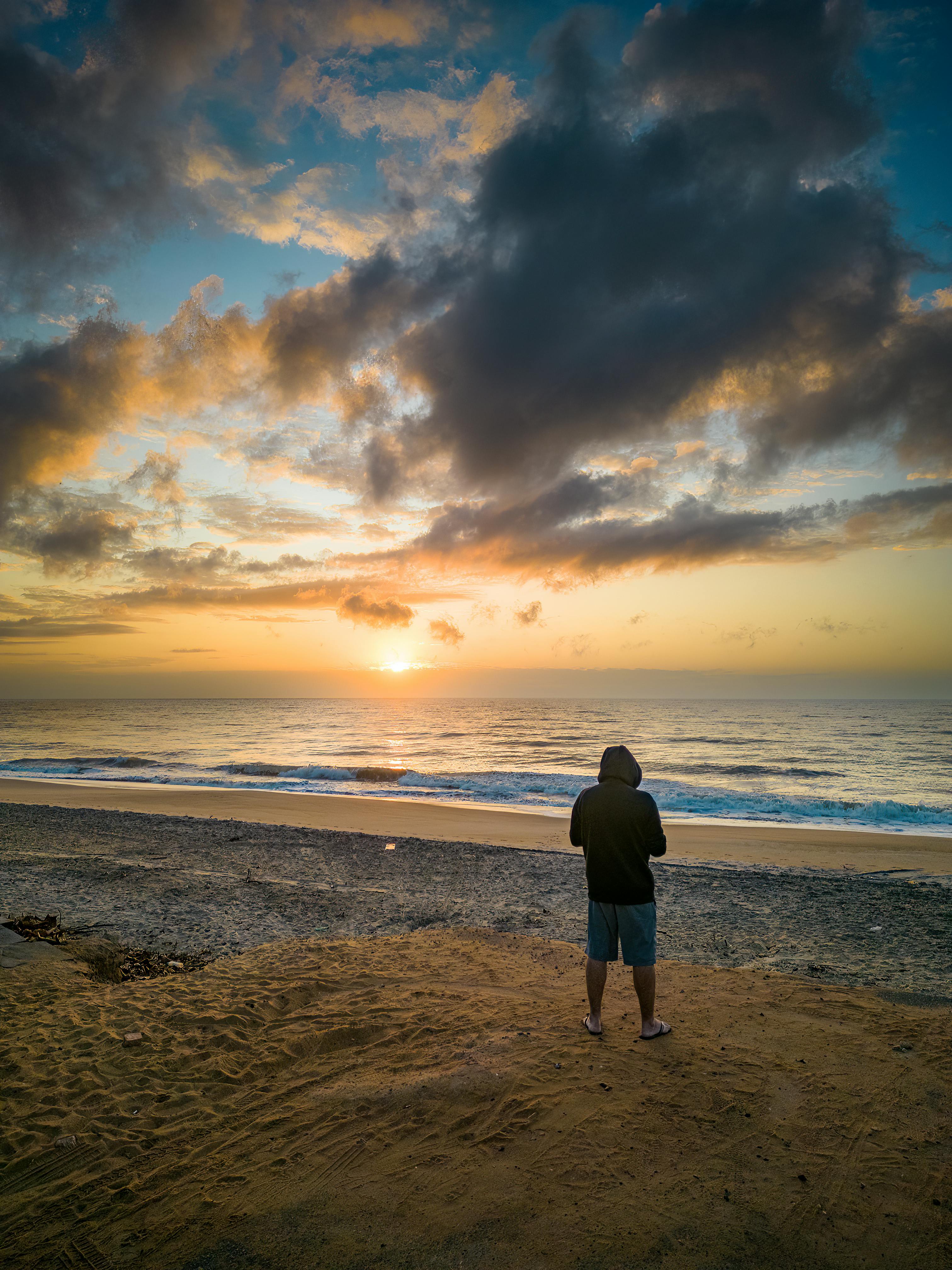 Back View of a Man Wearing a Hood, Standing on a Sandy Beach at Dusk ...