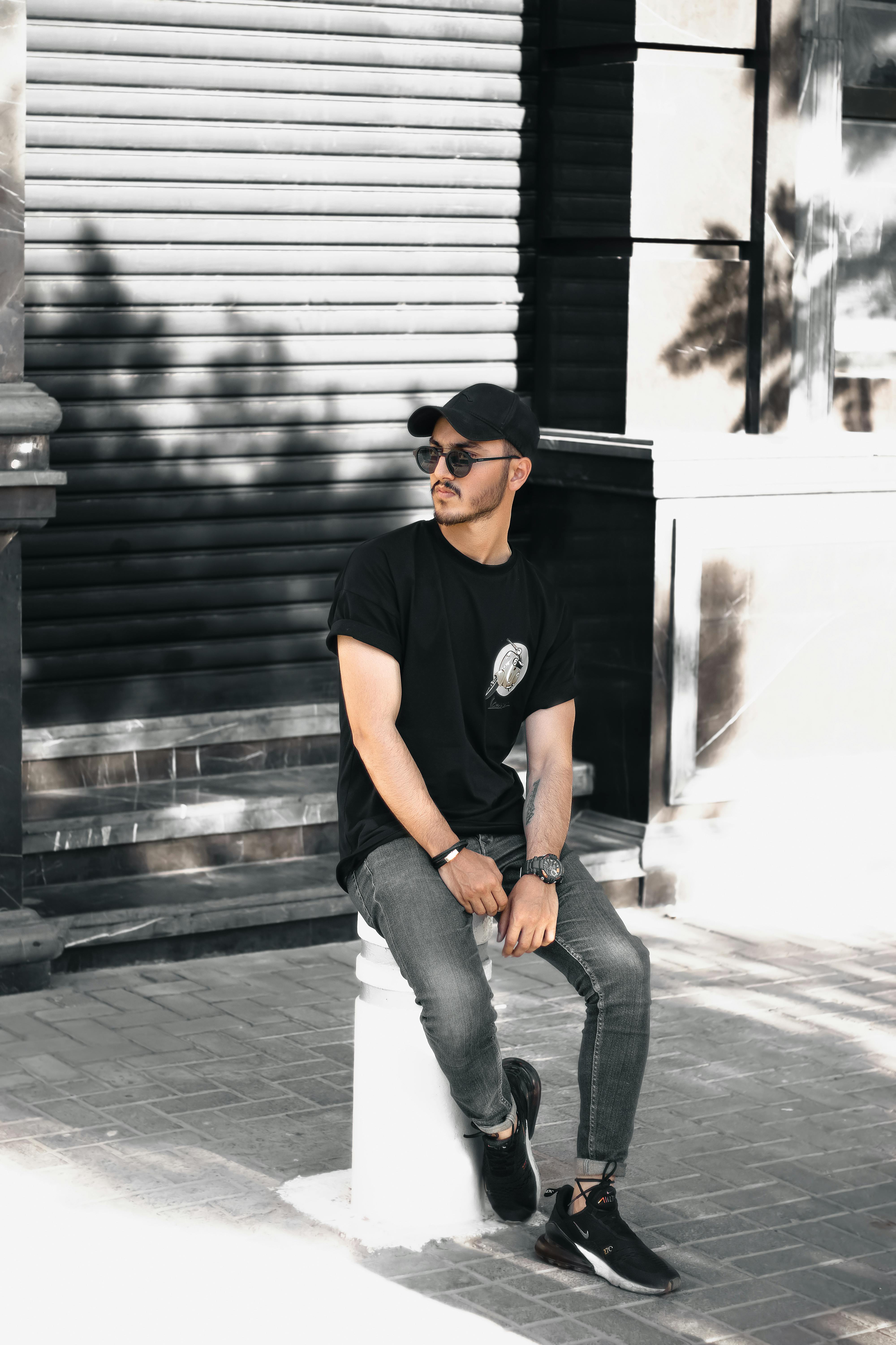 Man Sitting on Pole on Sidewalk · Free Stock Photo