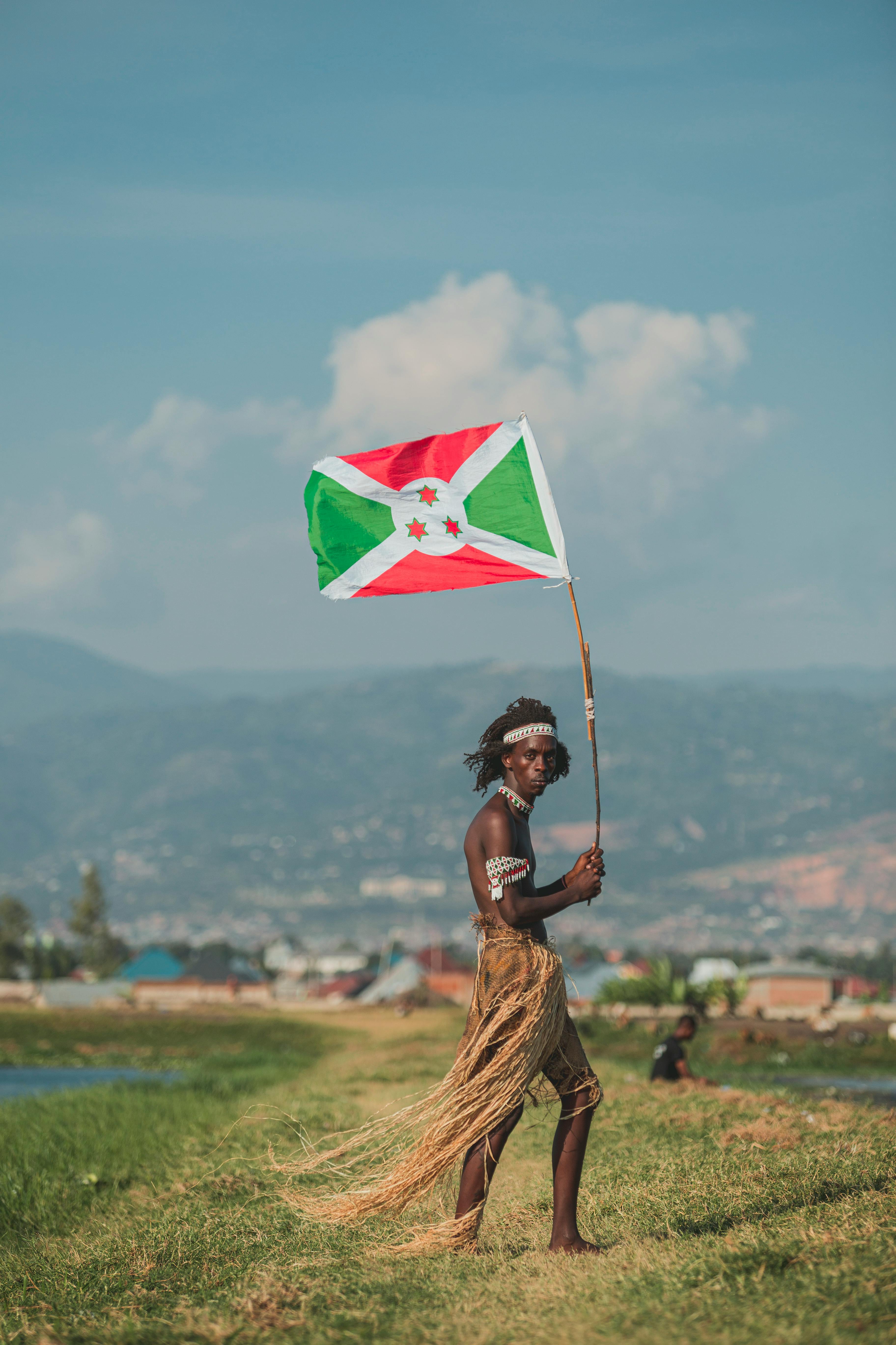 Man in Tribal Costume Holding Flag in Nature · Free Stock Photo