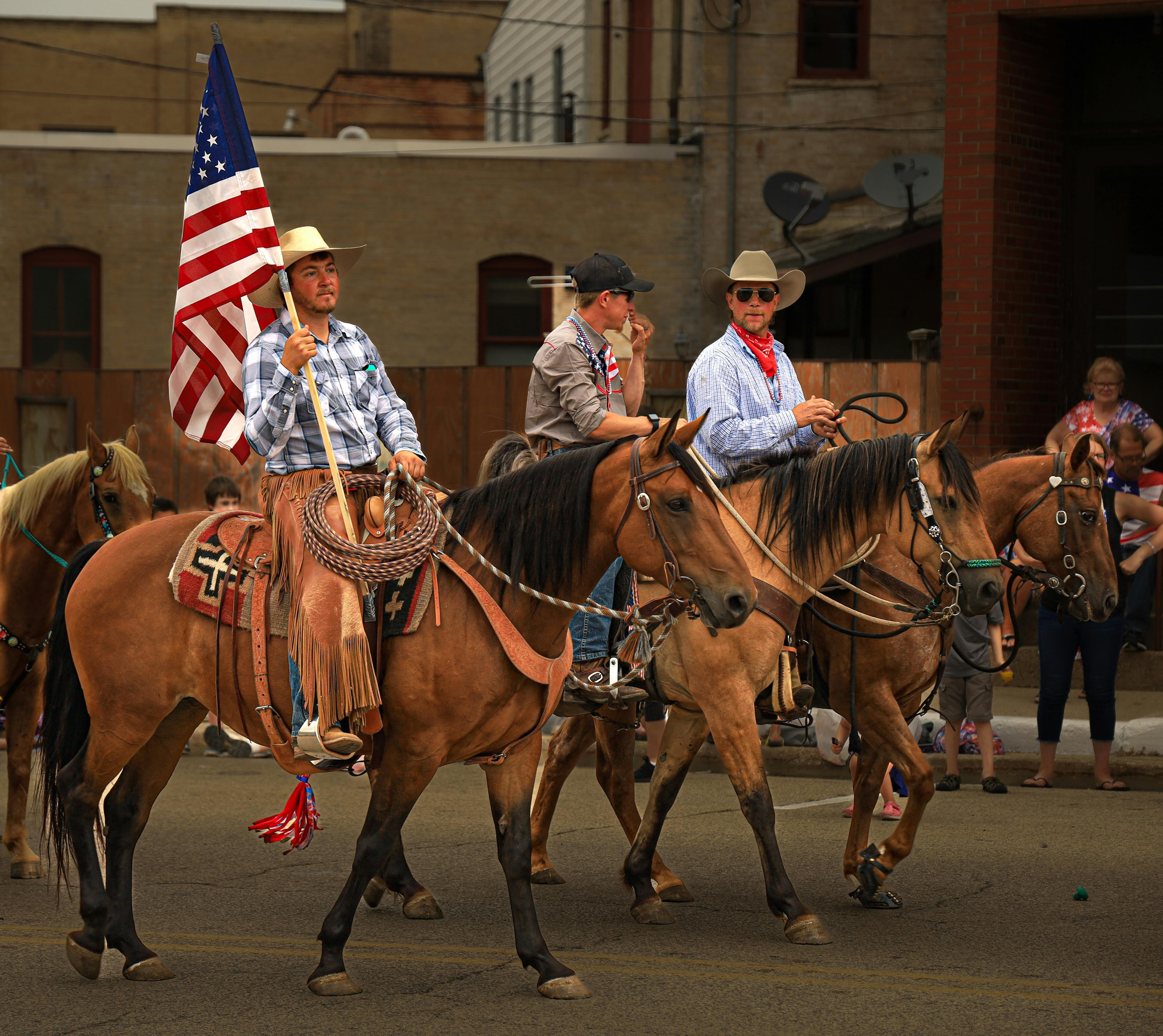 Cowboys with Flag Riding Horses on Street · Free Stock Photo