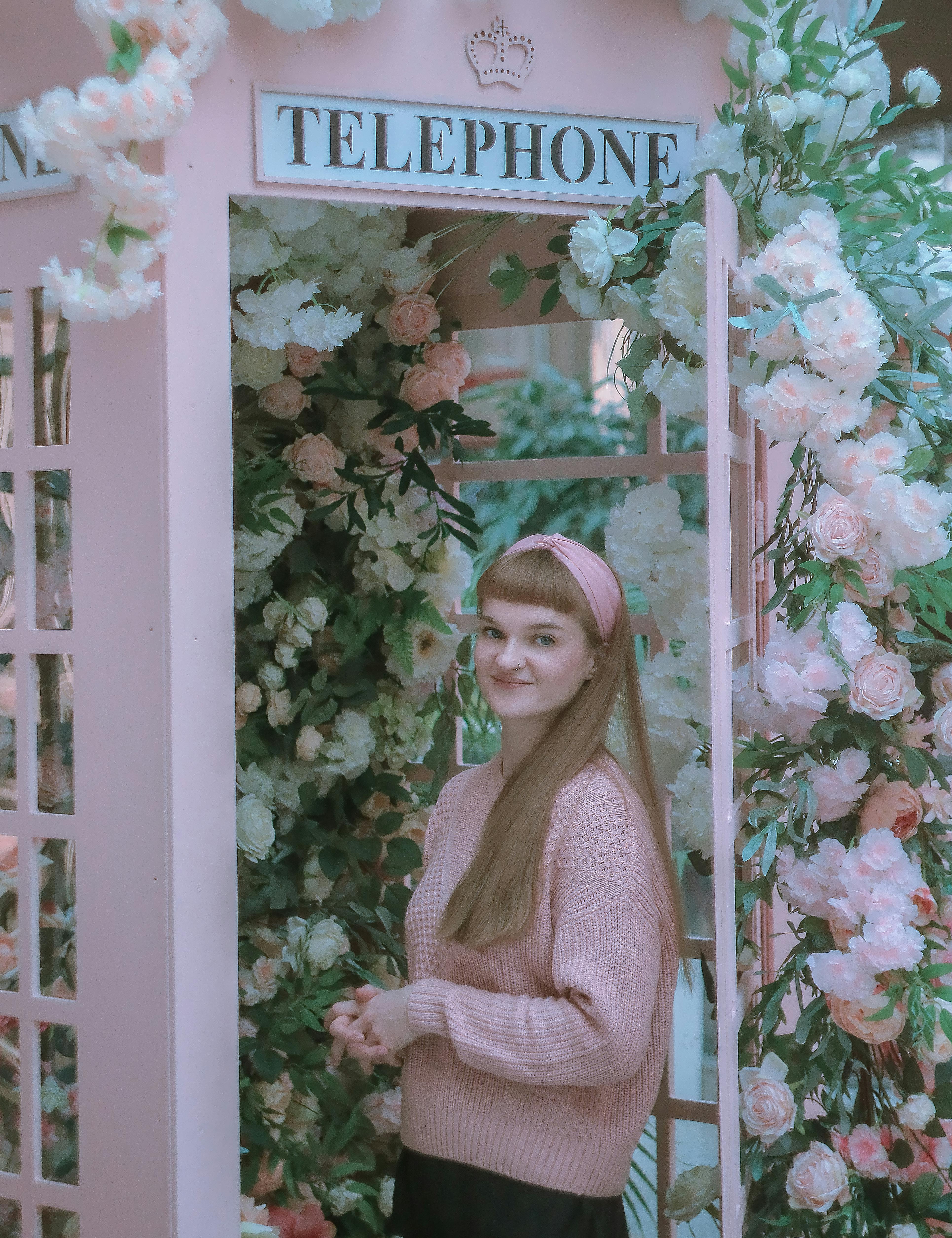 Young Woman in a Telephone Booth Decorated with Flowers · Free Stock Photo