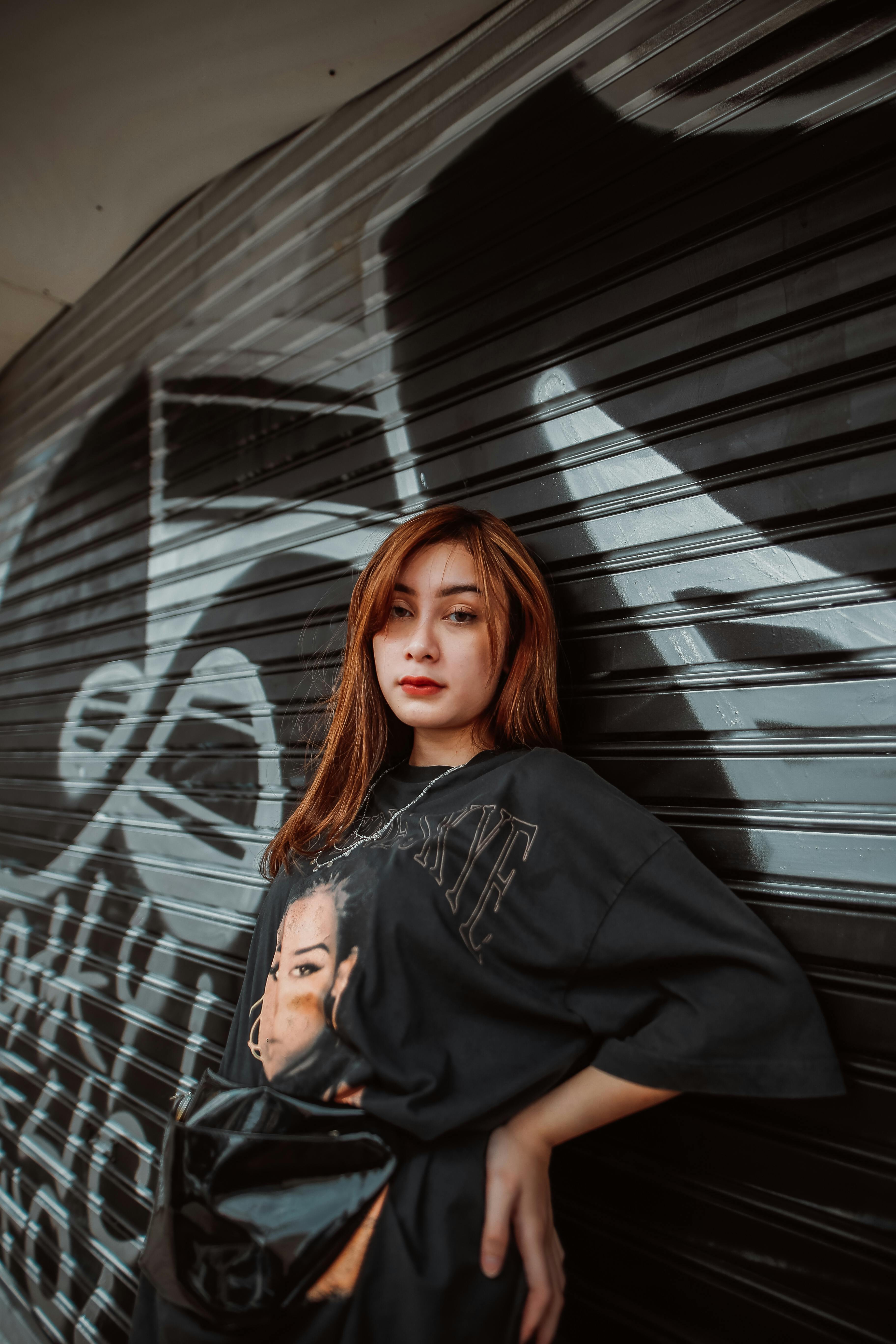Woman in Striped Shirt and Denim Jeans Leaning against a Ladder near ...