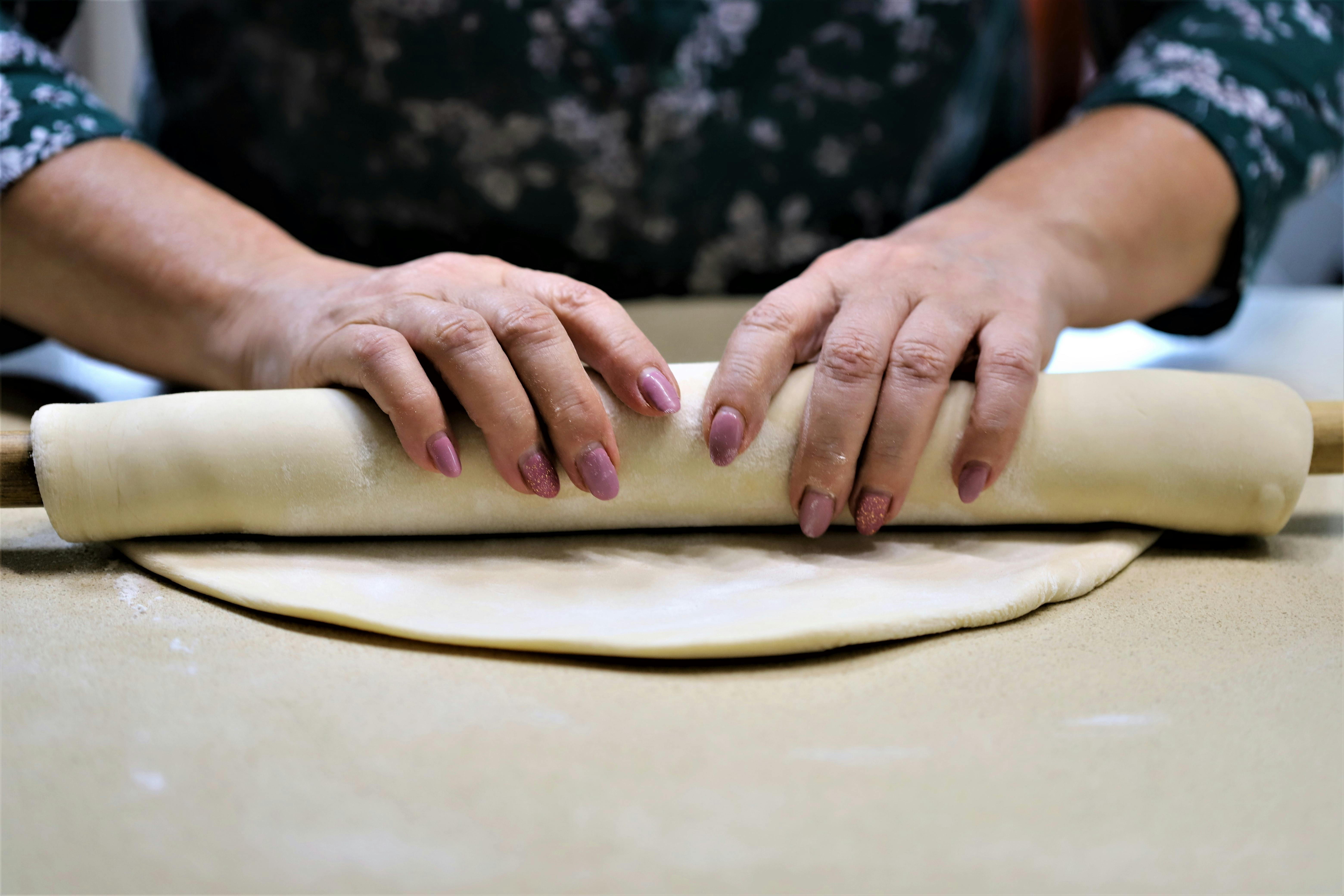 Person Rolling a Dough with Green Filling · Free Stock Photo